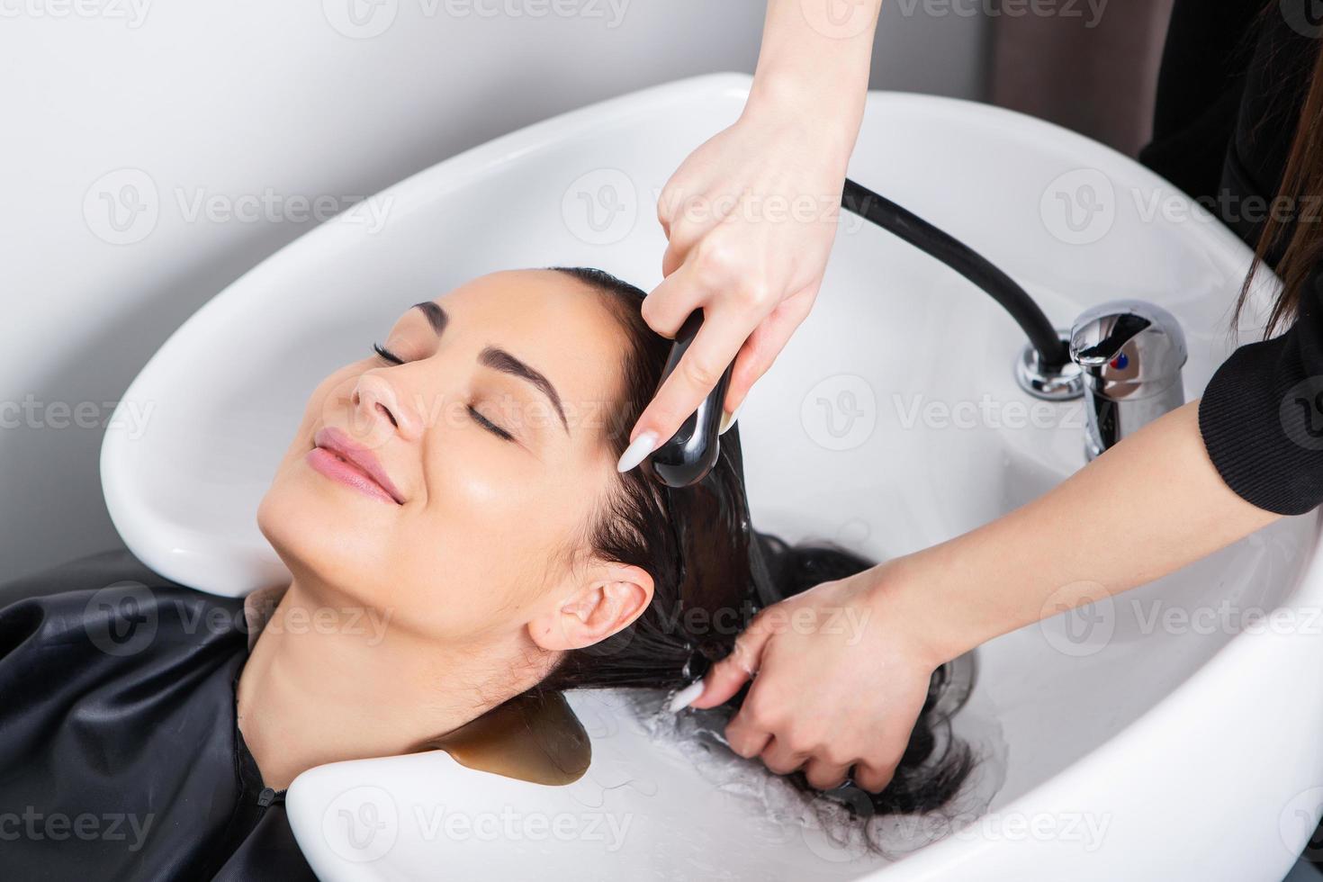 professional hairdresser washing hair of young woman in beauty salon.. close up of woman's hair ...