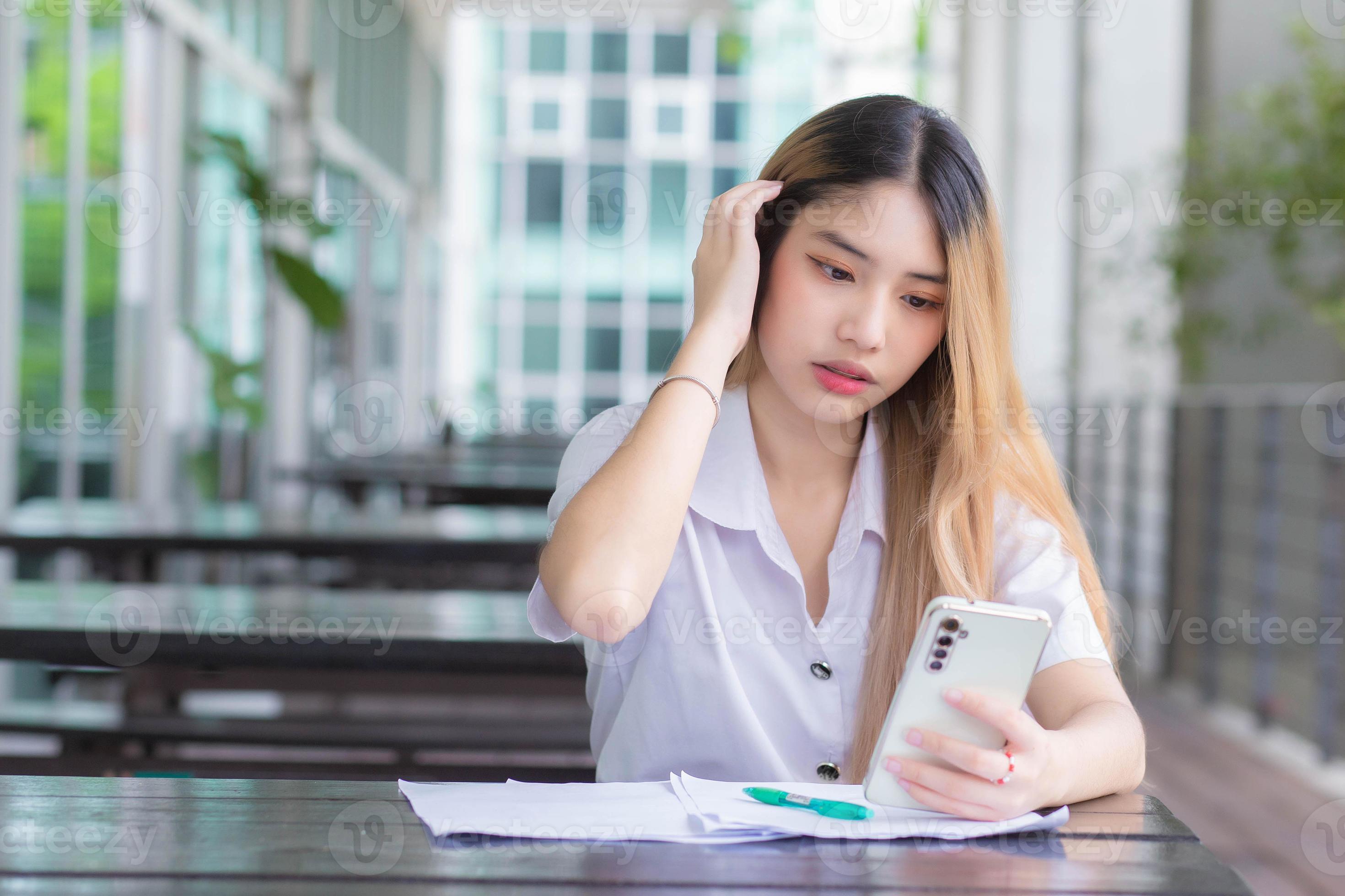 Portrait of cute Asian Thai girl student in uniform is sitting work smiling happily and ...