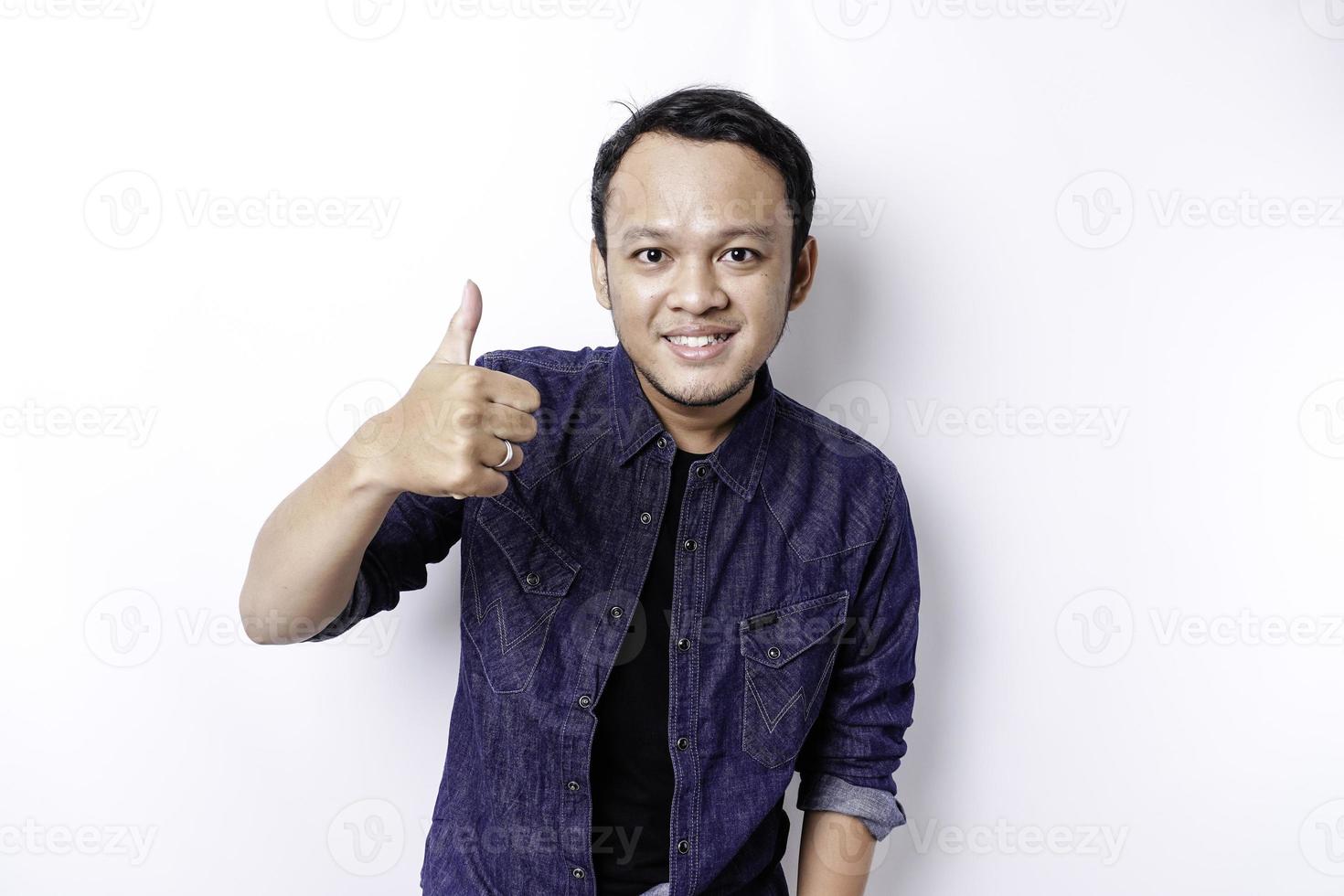 Excited Asian man wearing blue shirt gives thumbs up hand gesture of ...