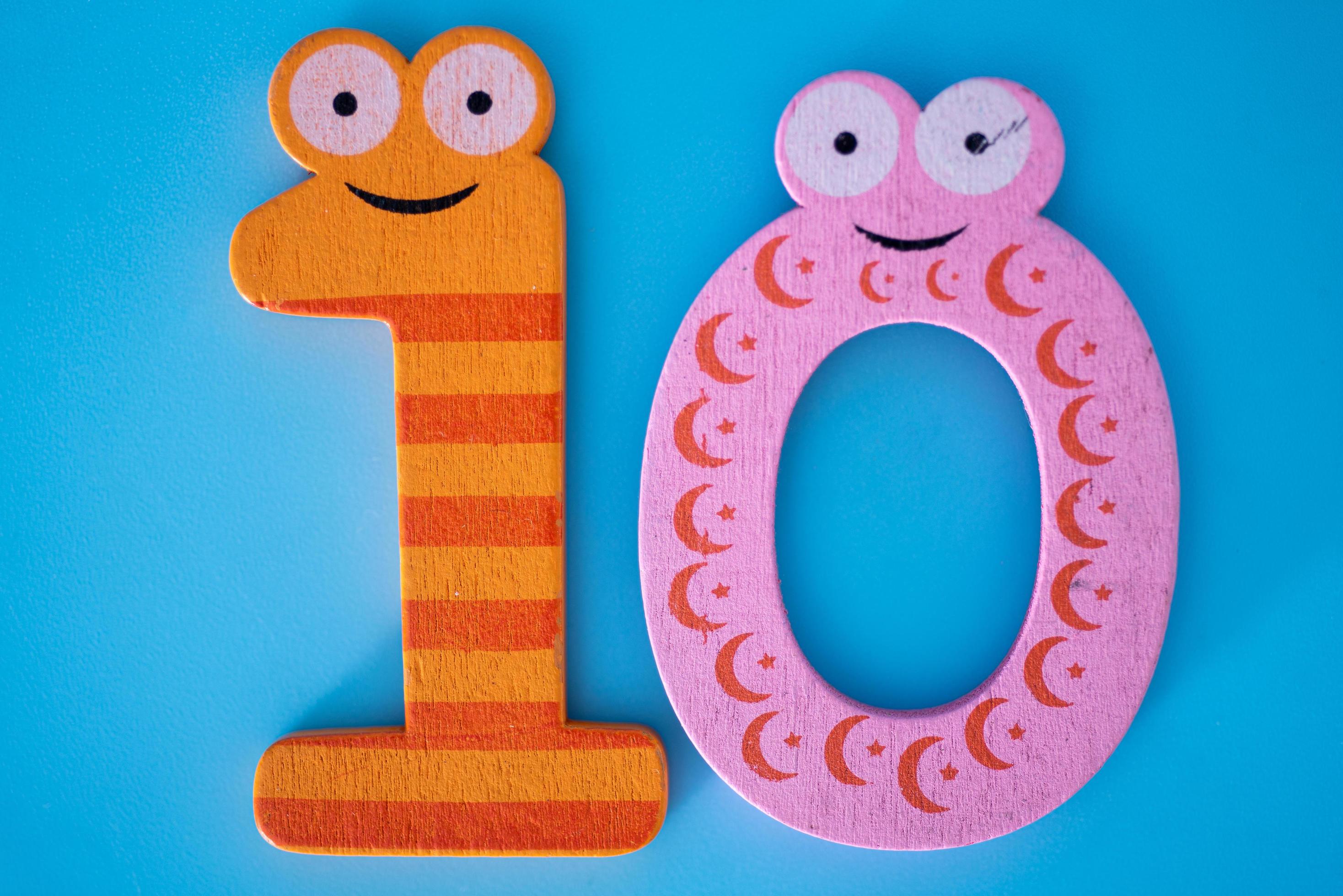 Cute and colorful wooden number 10 with eyes on a blue background ...