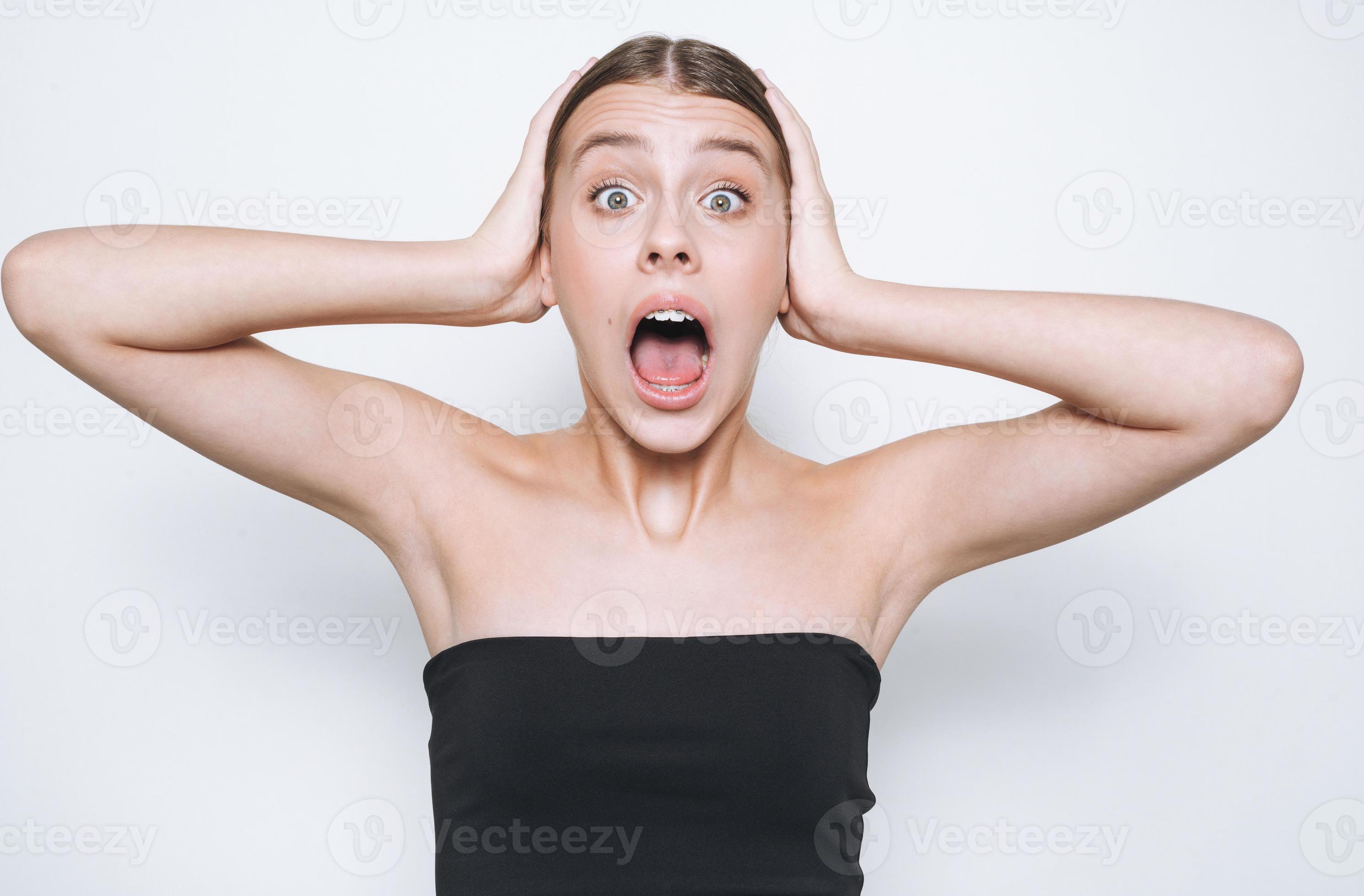 Portrait of surprised upset teenage girl frowns with hands near face on ...