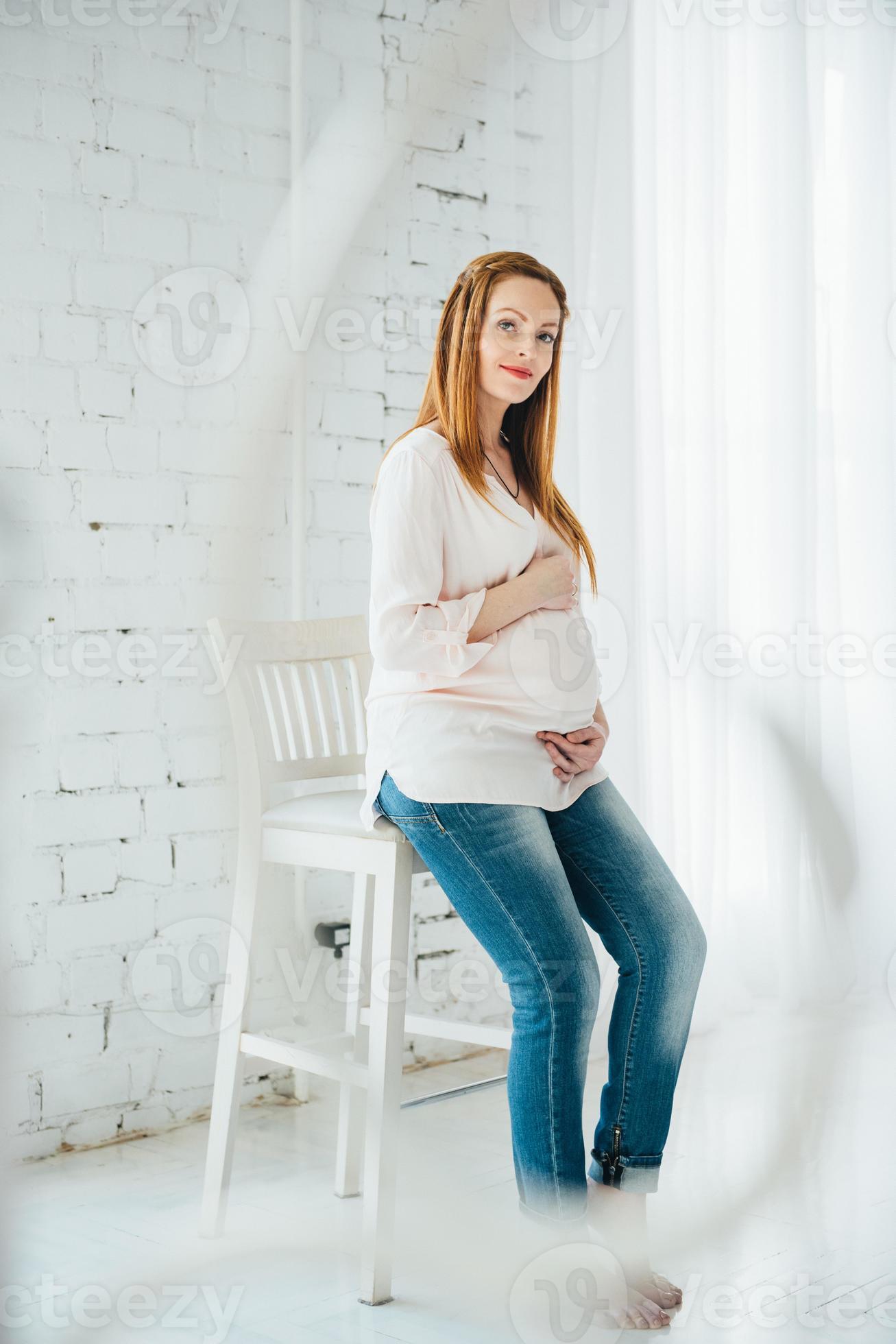 A Red Haired Pregnant Girl In A Light Blouse And Blue Jeans 18920900