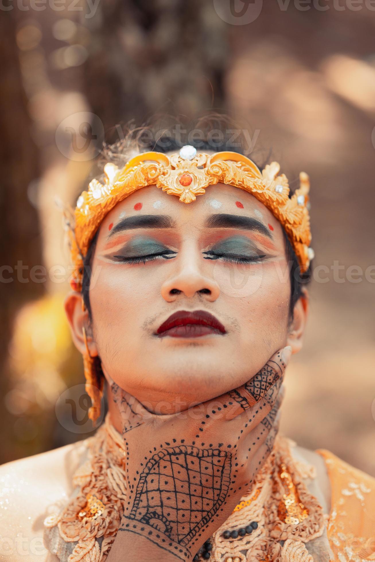 A Man Covering His Mouth With His Hand While In Golden Accessories