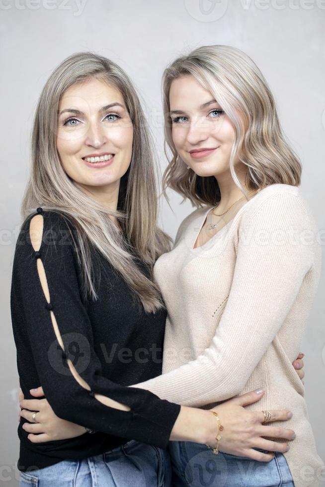 Beautiful middle-aged mother and adult daughter are hugging and looking at the camera. 19089188 ...