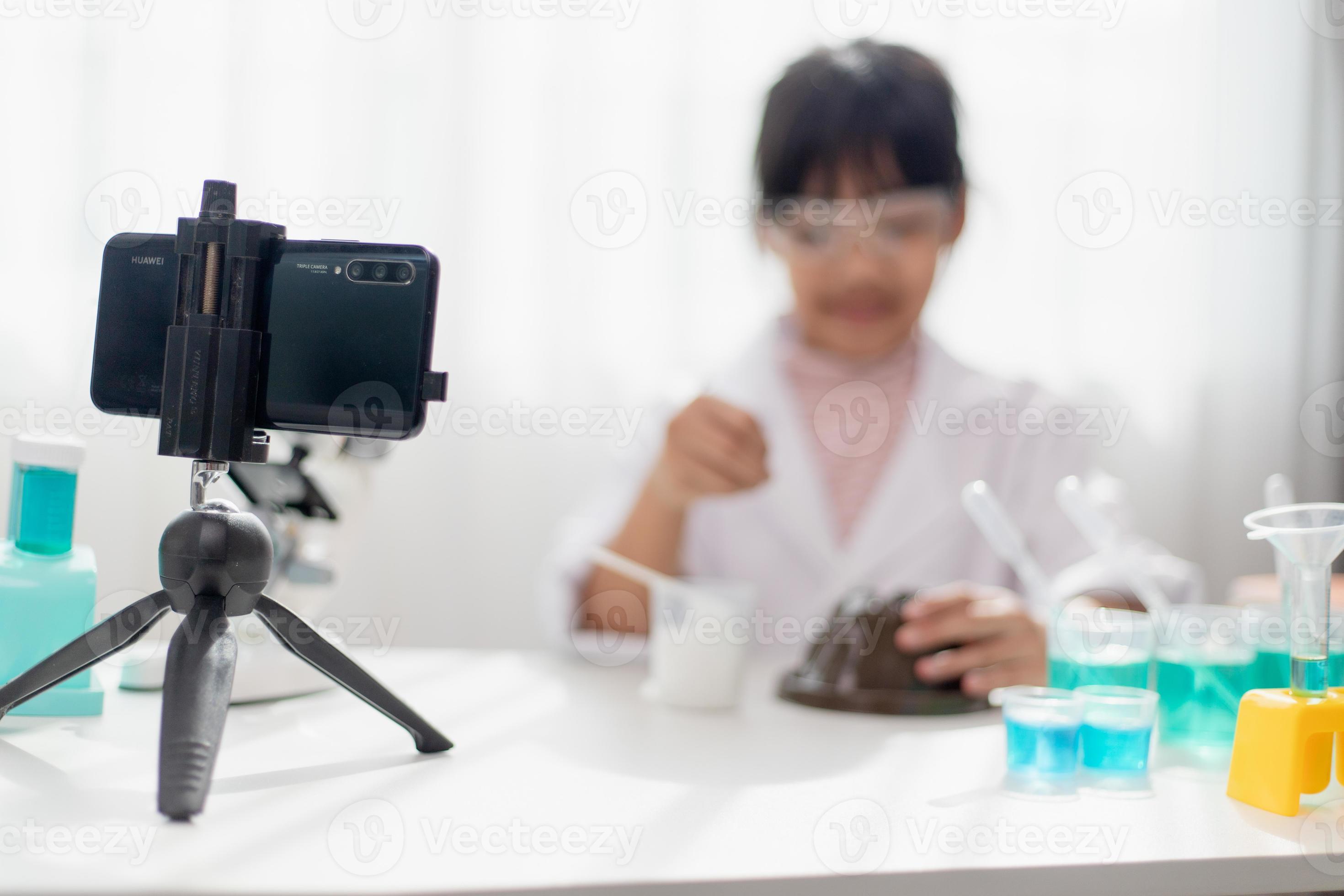 colegiala asiática haciendo experimentos de química fáciles y grabando un video para sus ...