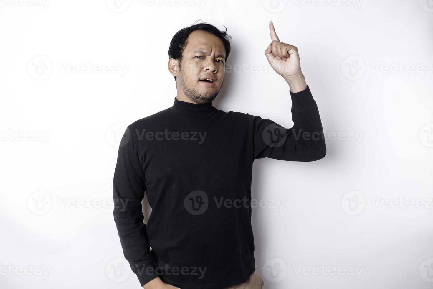Shocked Asian man wearing black shirt pointing at the copy space on top ...