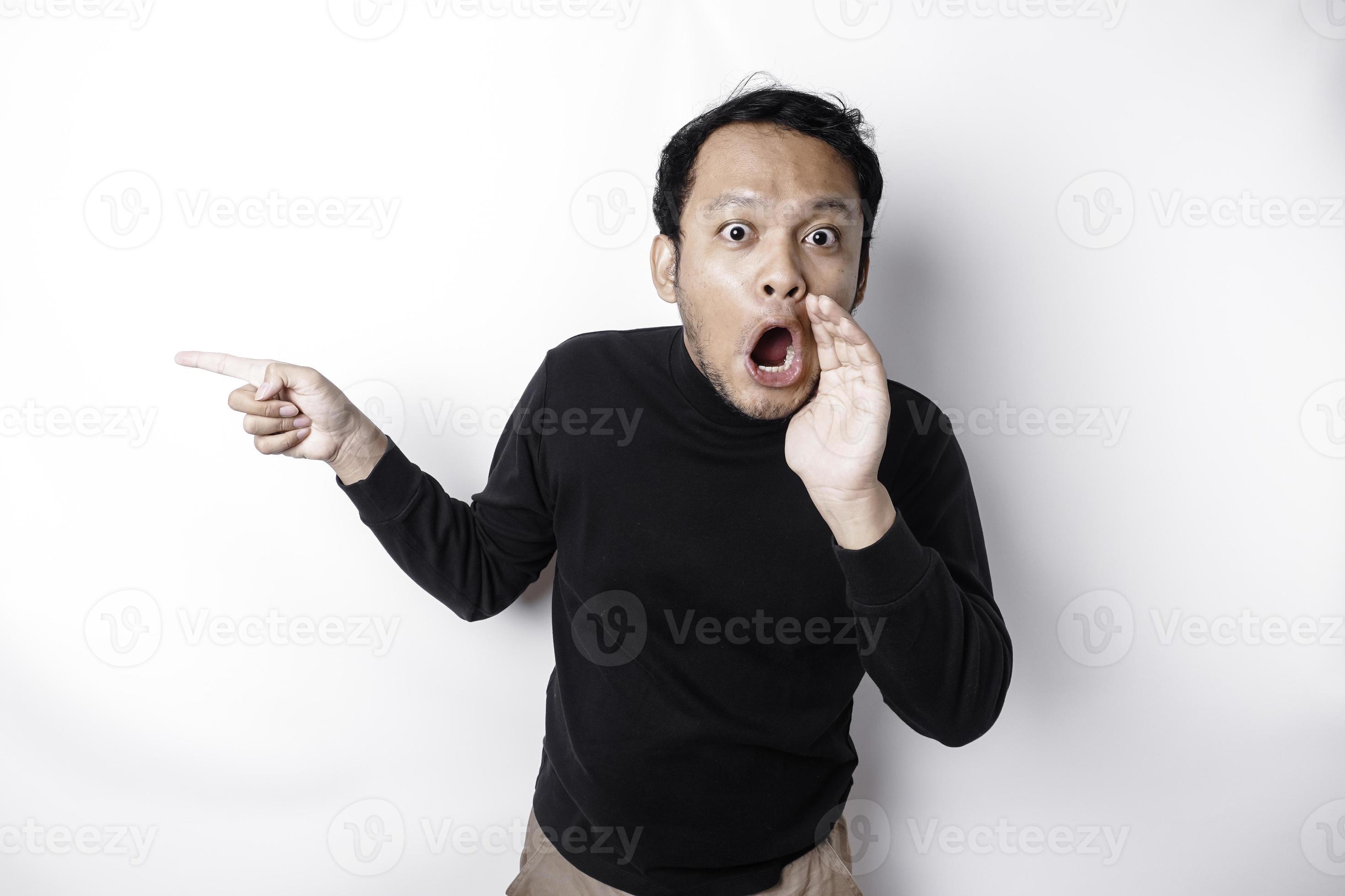 Shocked Asian man wearing black shirt pointing at the copy space beside ...
