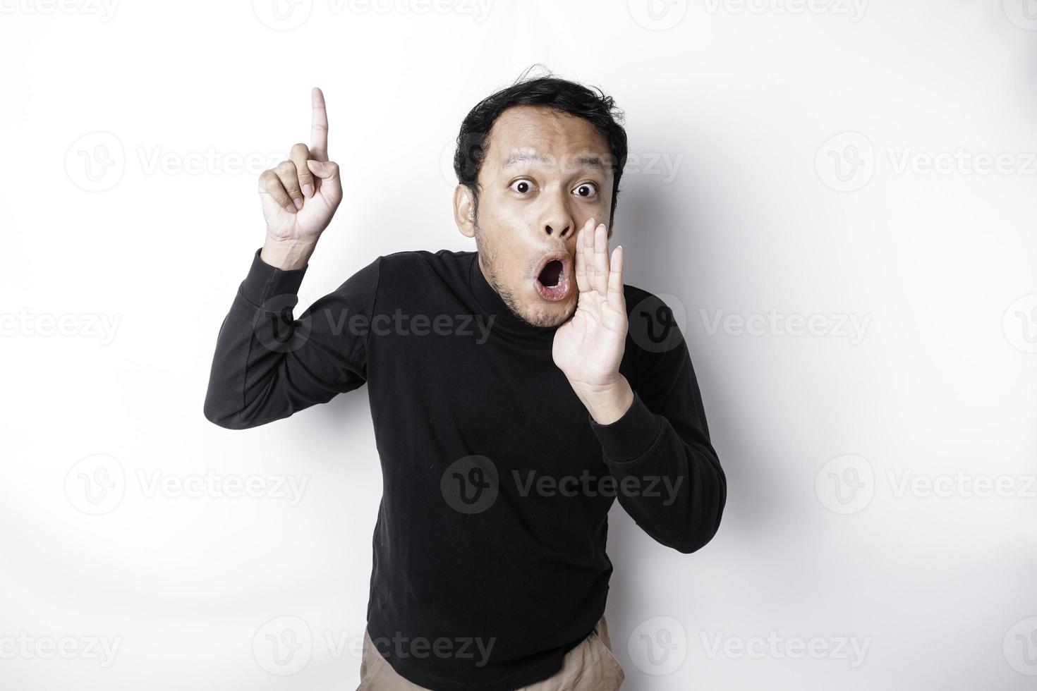 Shocked Asian man wearing black shirt pointing at the copy space on top ...