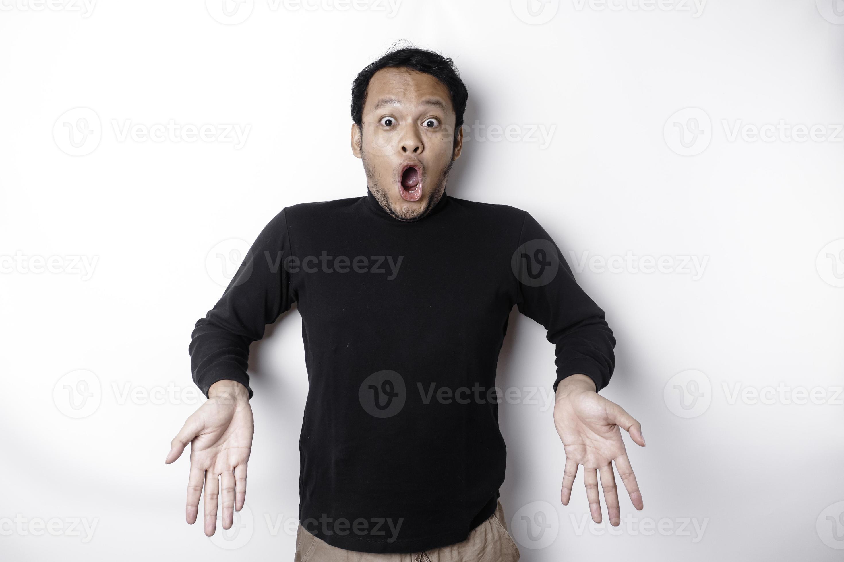 Shocked Asian man wearing black shirt, pointing at the copy space below ...