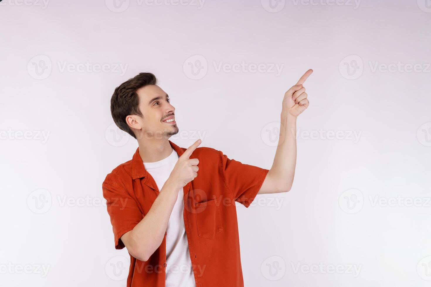 Portrait of young man pointing fingers at copy space isolated on white ...