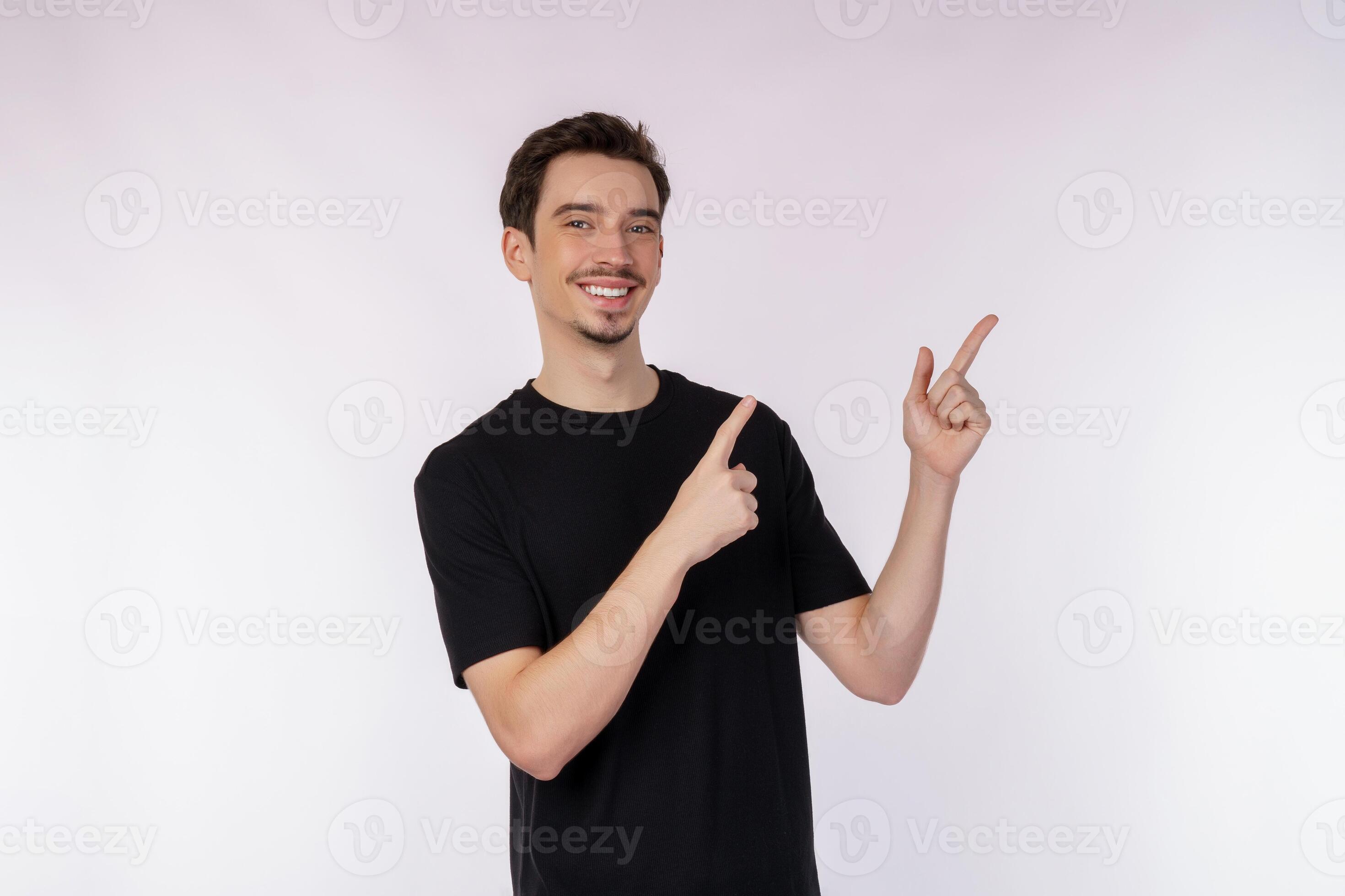 Portrait of young man pointing fingers at copy space isolated on white ...