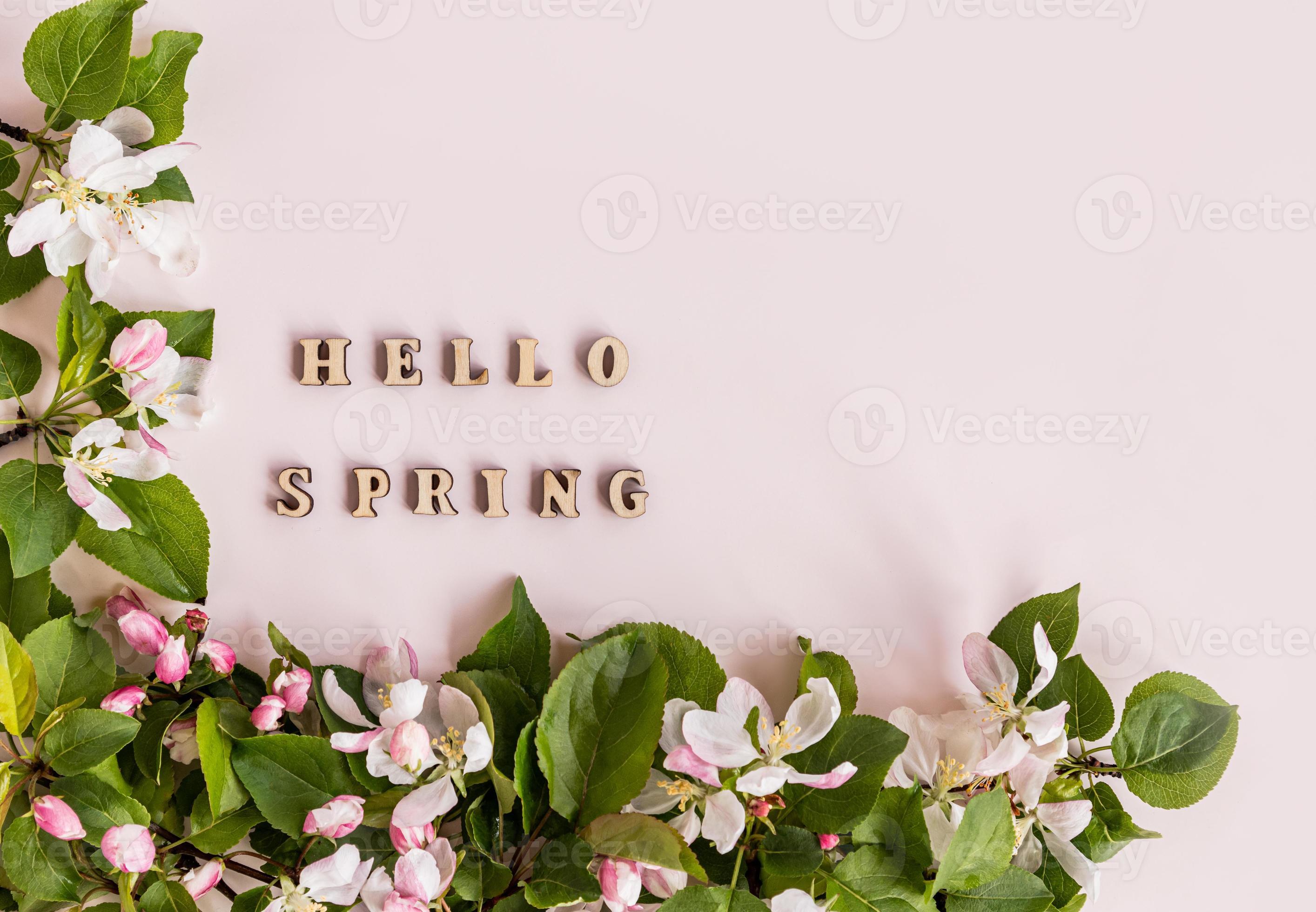 top view of the flowering branches of an apple tree and wooden letters with the text hello ...