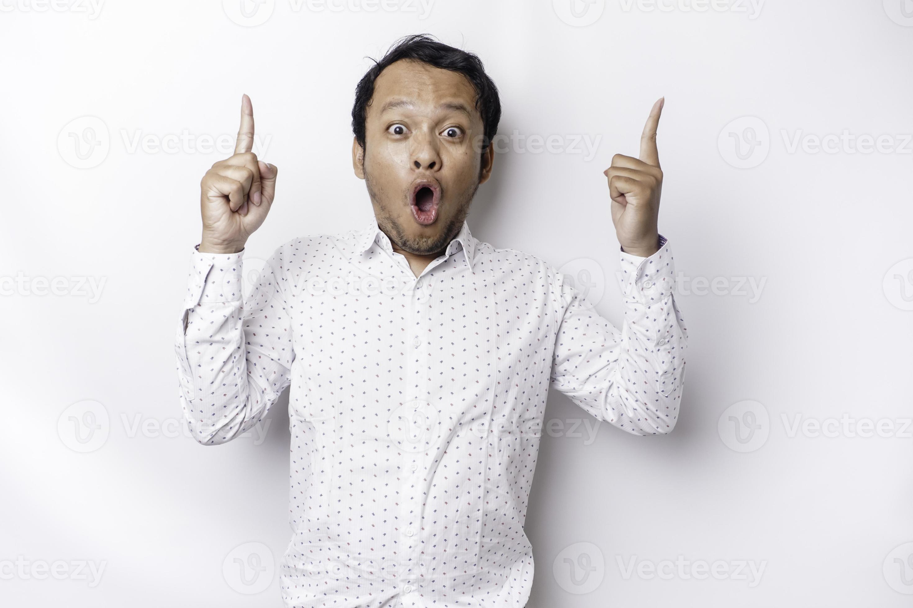 Shocked Asian man wearing white shirt pointing at the copy space on top ...