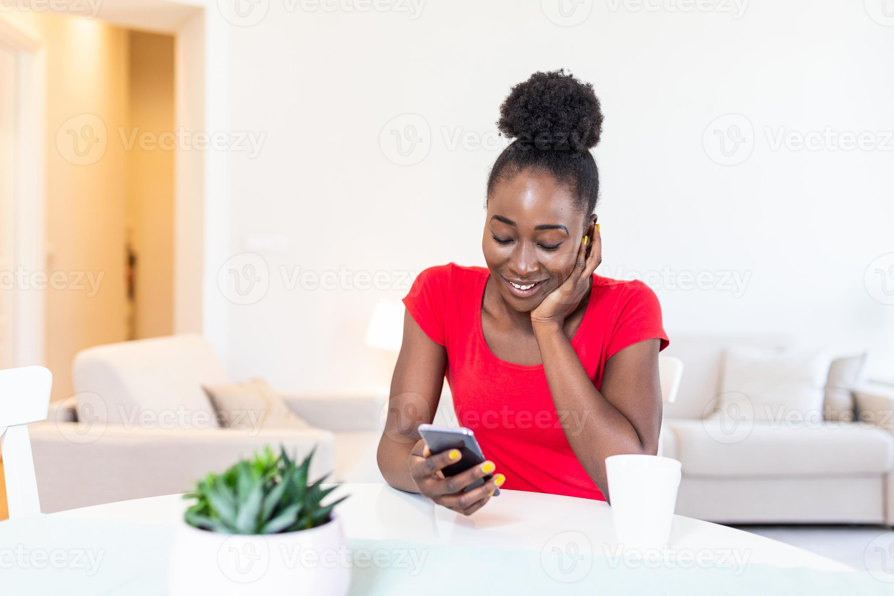 Young woman sitting on table and enjoying first morning coffee in cozy apartment. Smiling woman ...
