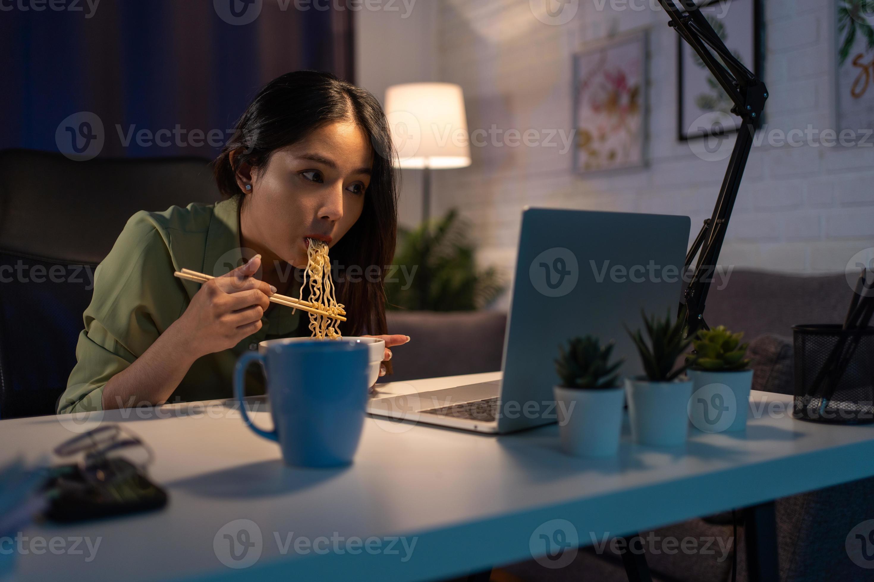 Asian Young Woman Eating Instant Noodles While Watching Video Movie On Tablet And Reading News