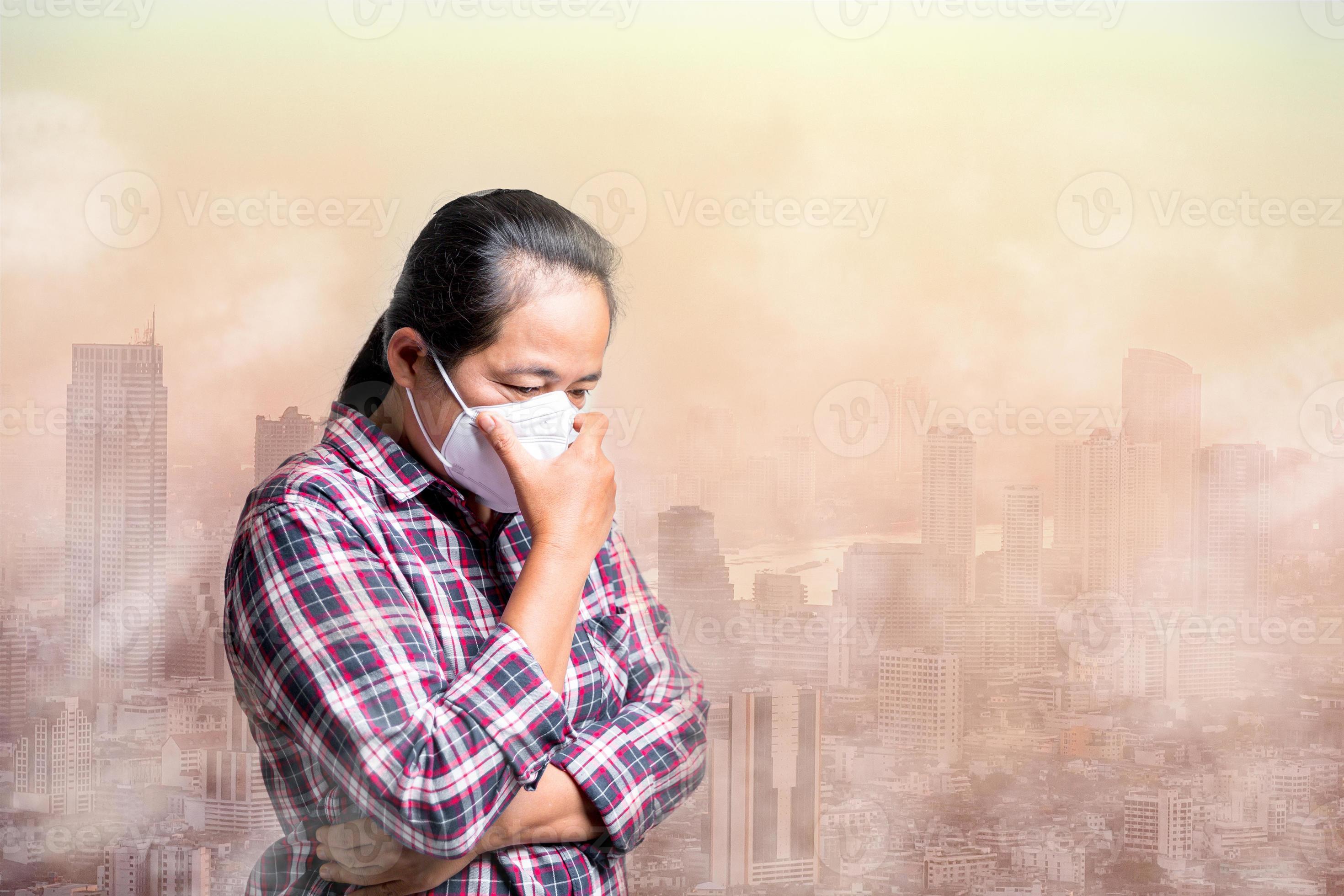 Woman wearing N95 PM 2.5 respiratory protection mask against air pollution and dust particles ...