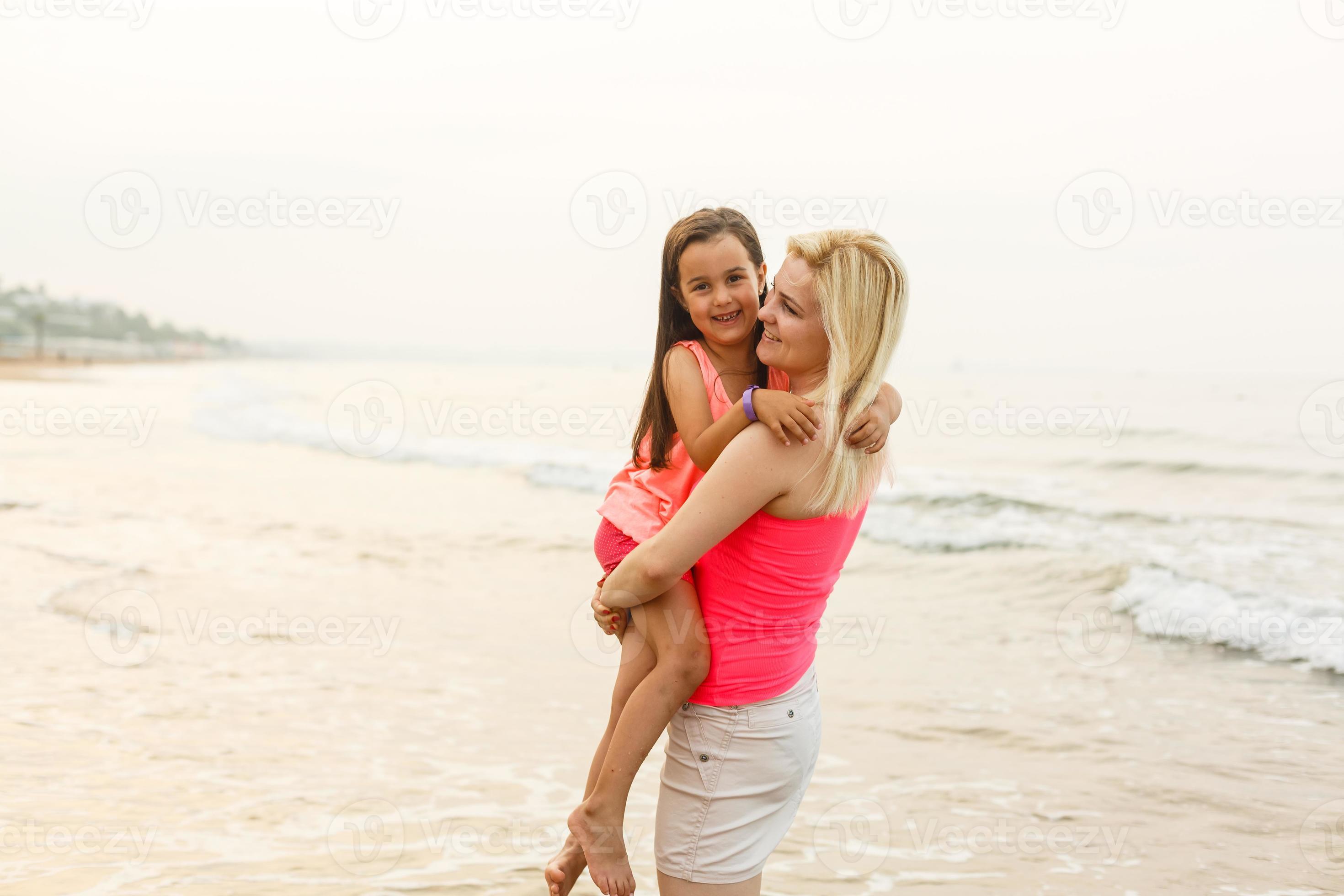 Happy loving family mother and daughter having fun on the beach at sunset - Mum playing with her ...