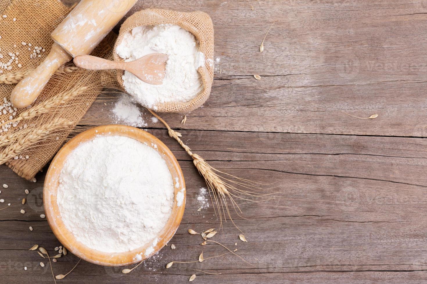 wheat flour in a wooden bowl There are ears of wheat on the table. Old wooden background - top ...