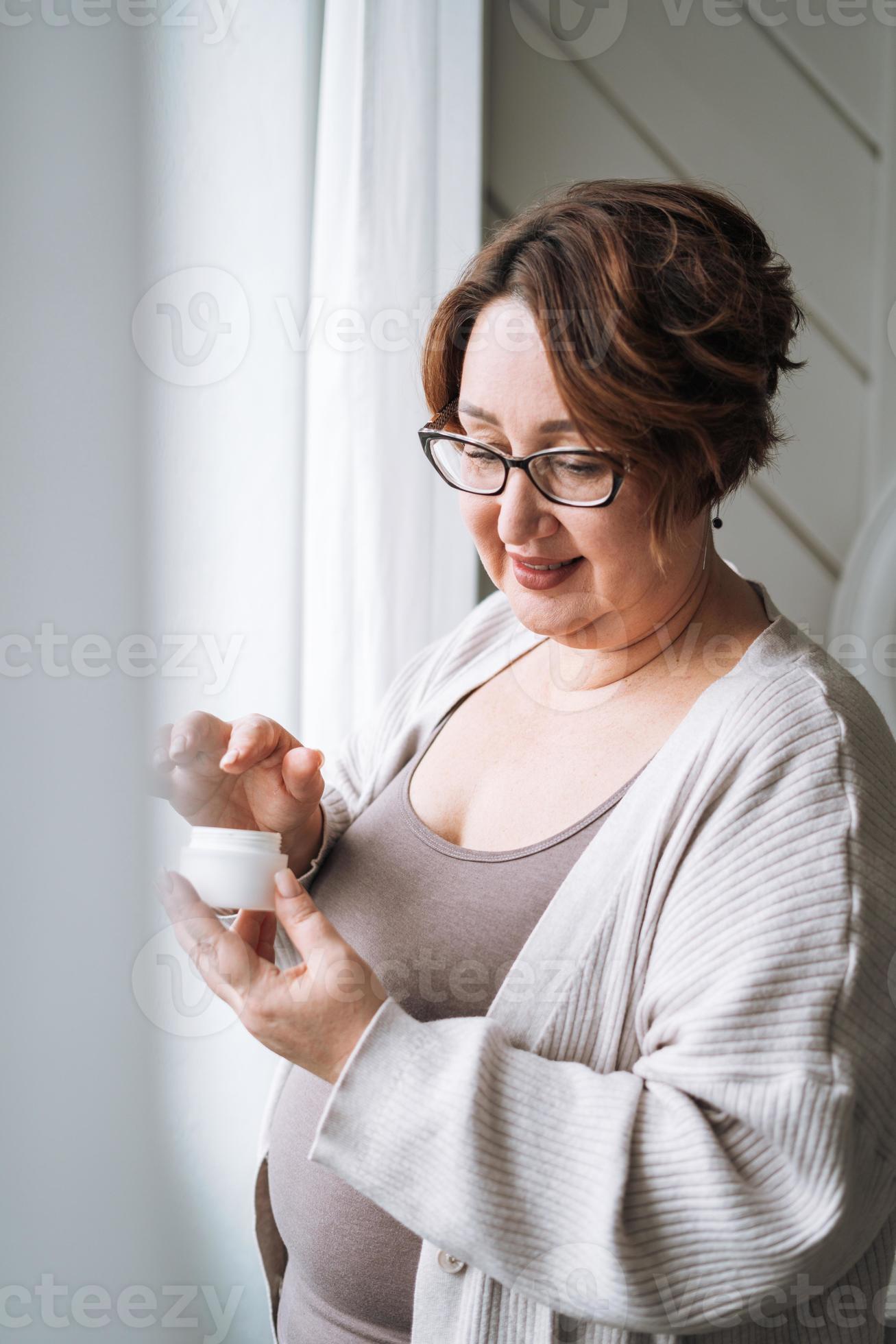 Smiling middle aged plus size woman with day cream near window at home 21033276 Stock Photo at ...