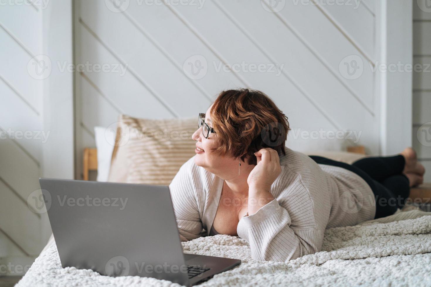 Smiling middle aged plus size woman lying on bed, working on laptop from home 21033285 Stock ...