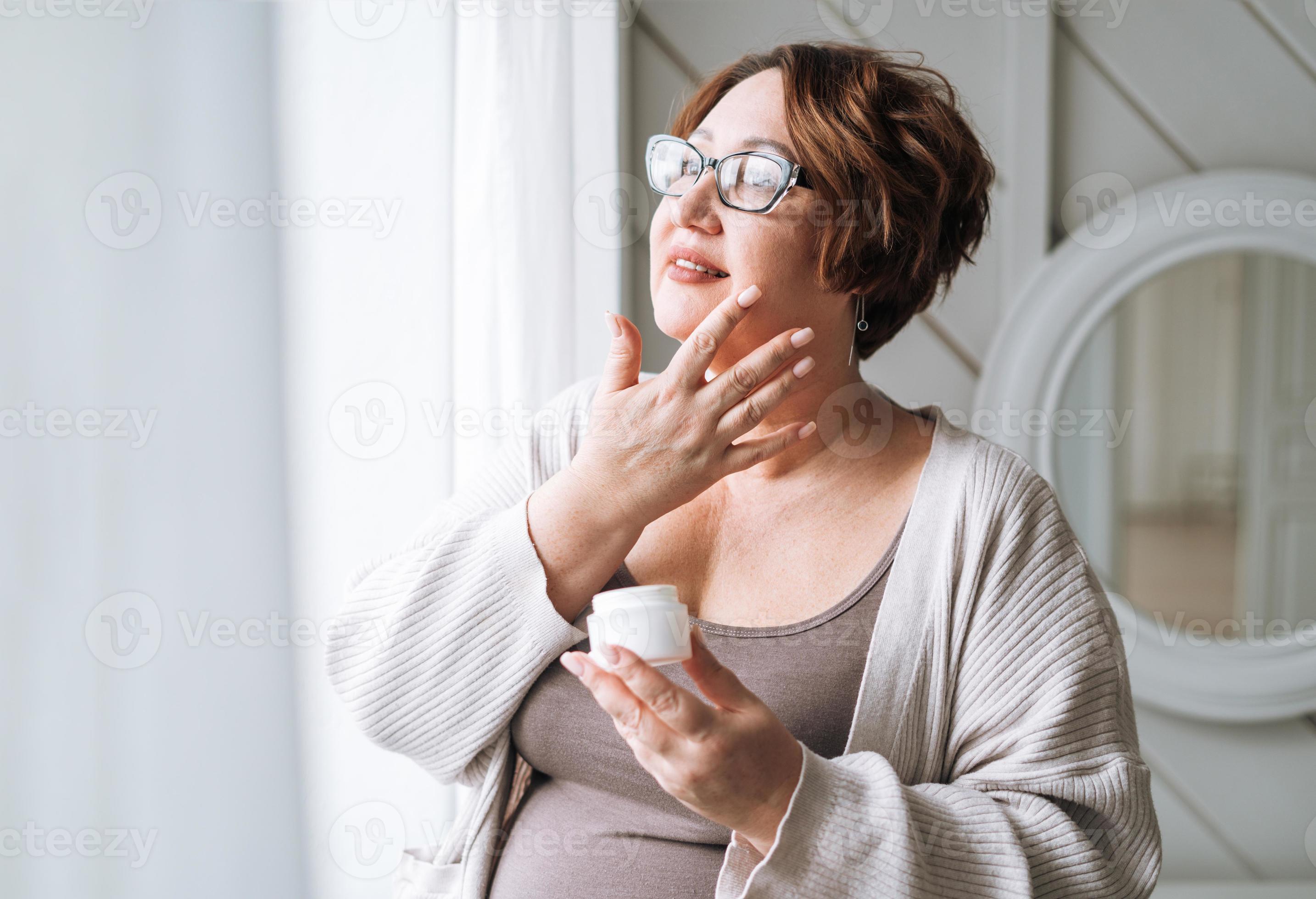 Smiling middle aged plus size woman with day cream near window at home 21033302 Stock Photo at ...