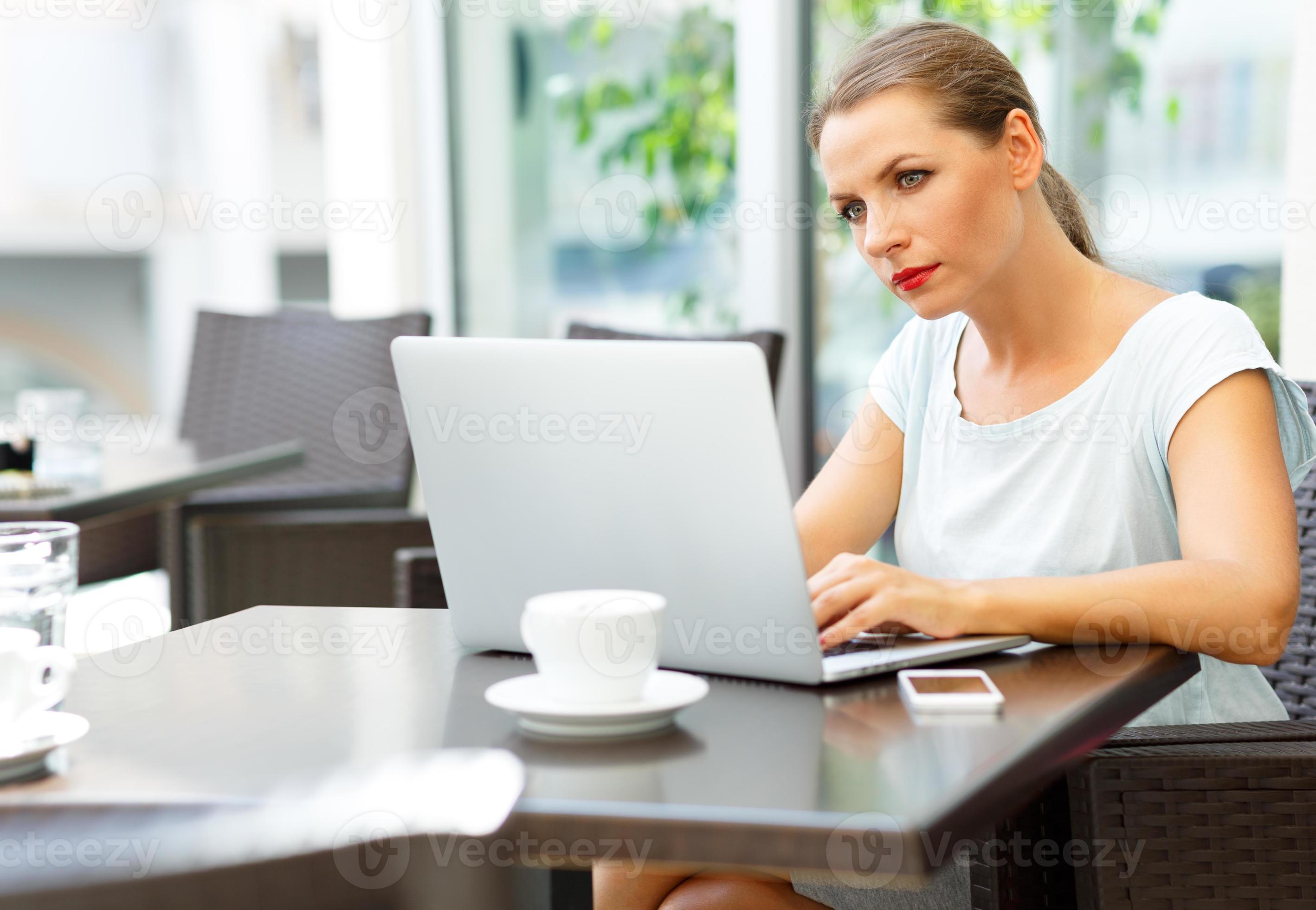 Young business woman sitting in a cafe with a laptop and coffee ...
