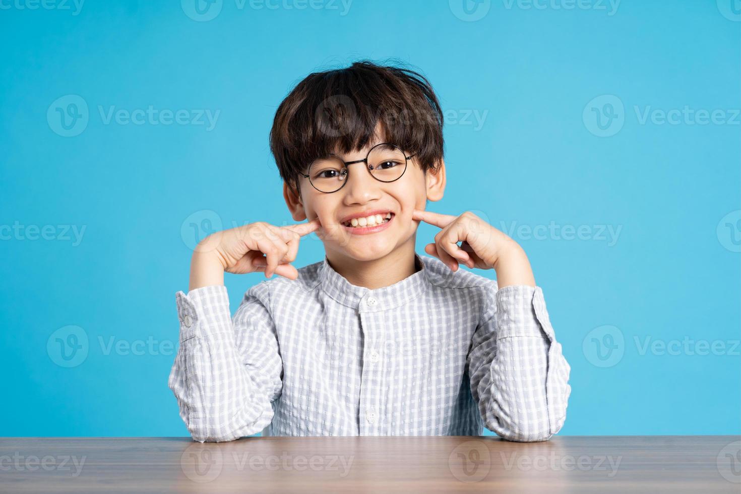 portrait of school boy sitting and studying on a blue background ...