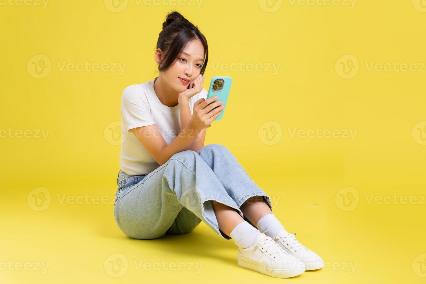 Portrait Of A Beautiful Young Asian Girl Sitting On A Yellow Background