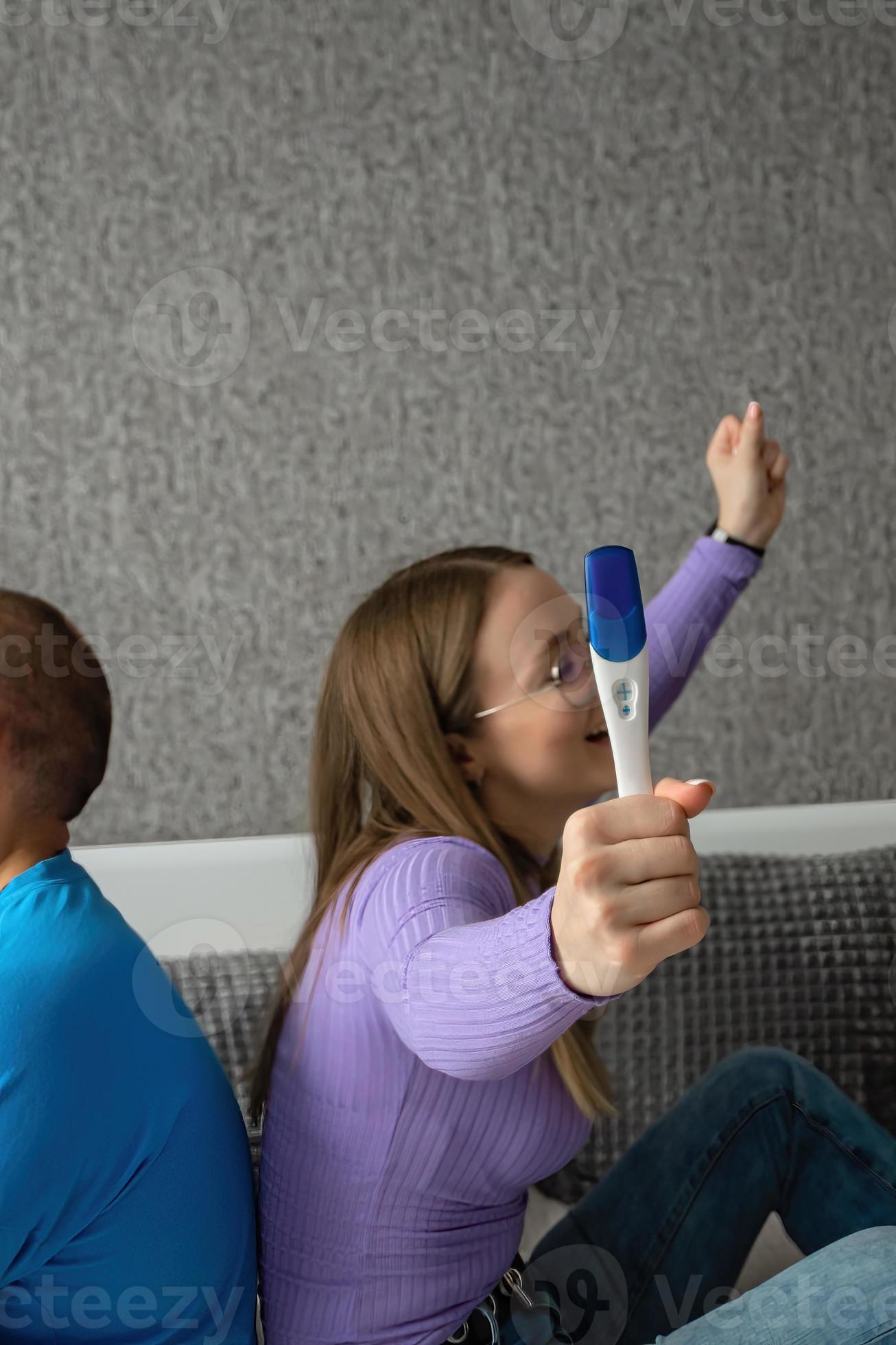 A man and a woman sit back to back on the bed, the woman rejoices and ...