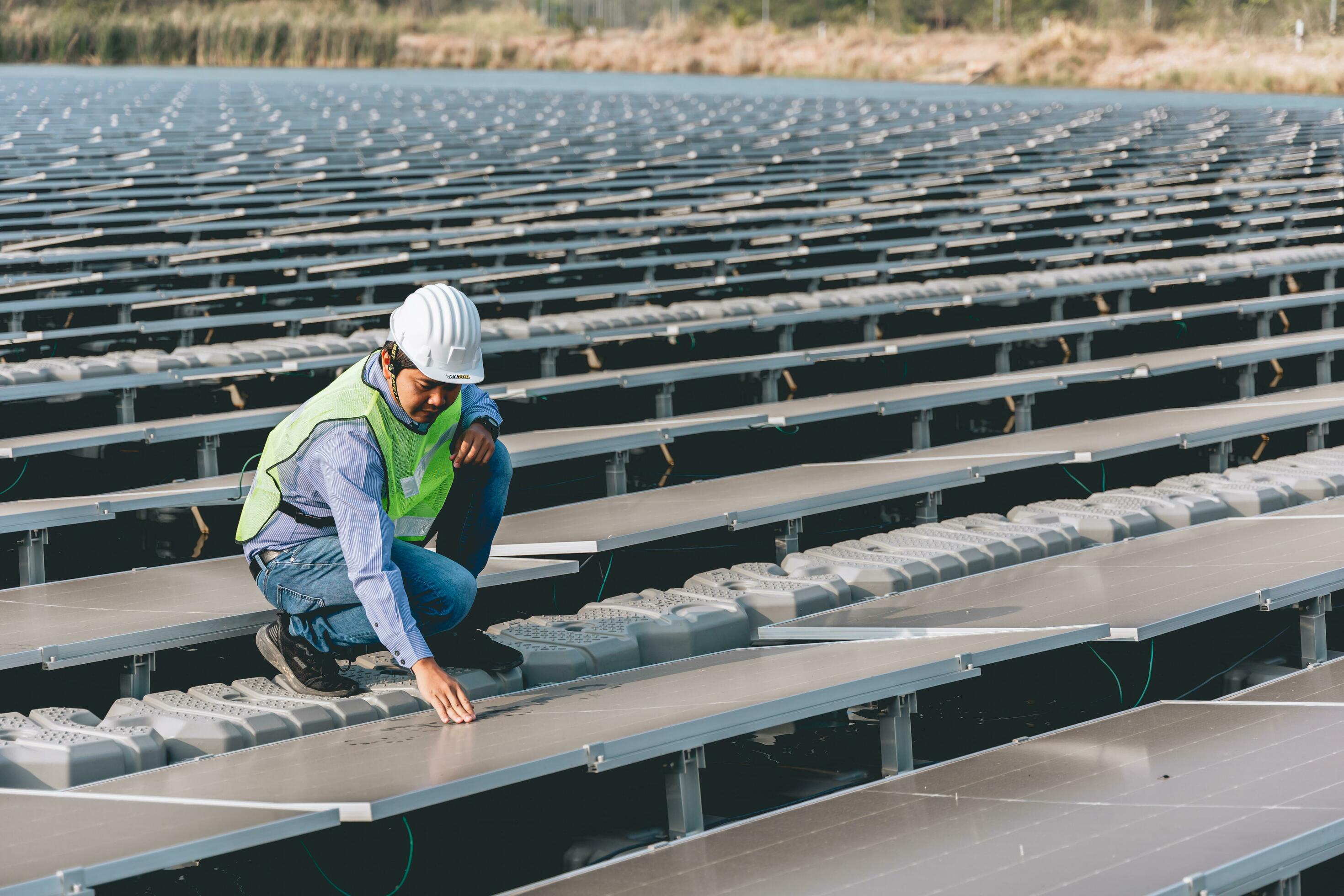 Engineer inspector holding laptop and working in solar panels power plant checking photovoltaic ...