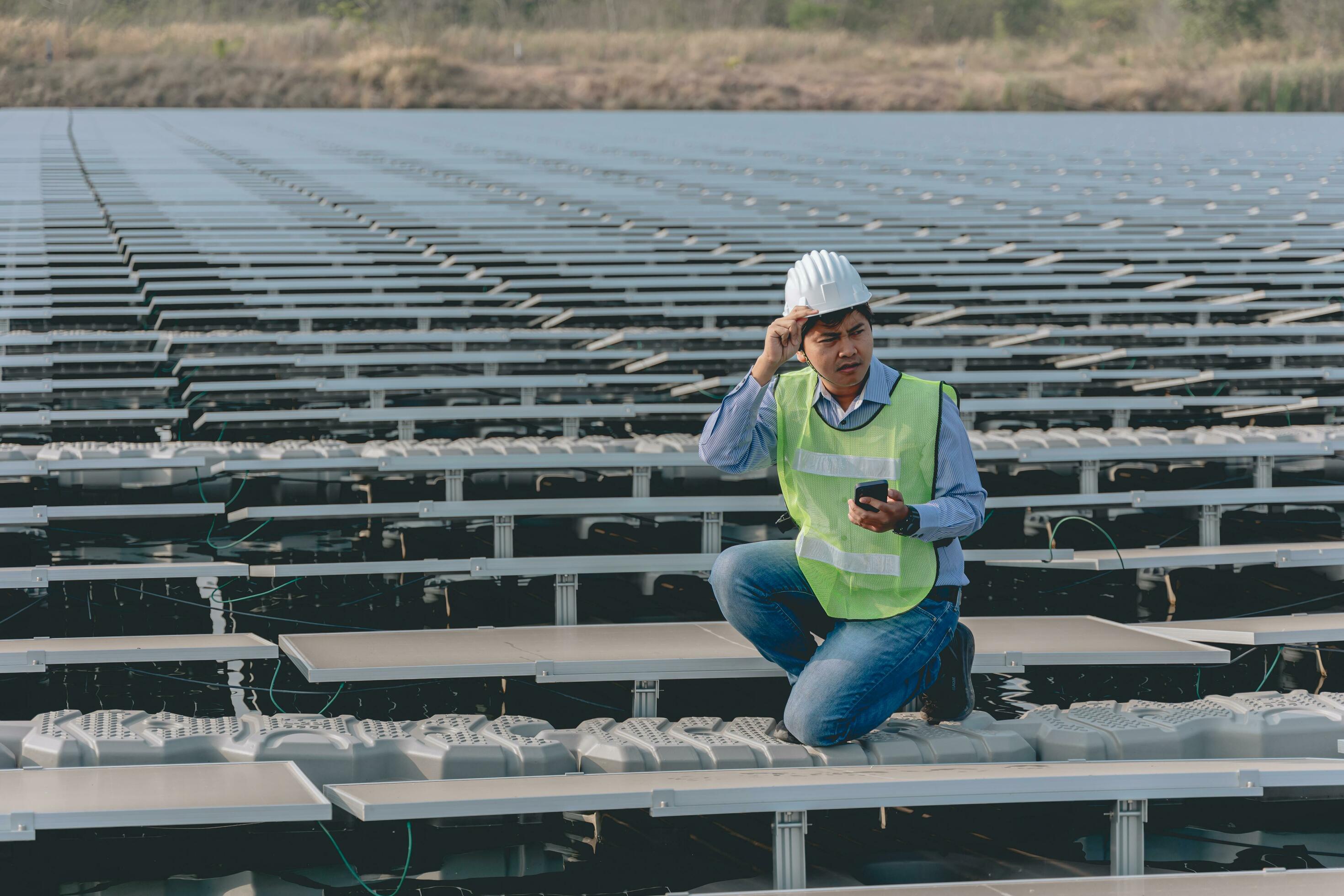 Engineer inspector holding laptop and working in solar panels power plant checking photovoltaic ...