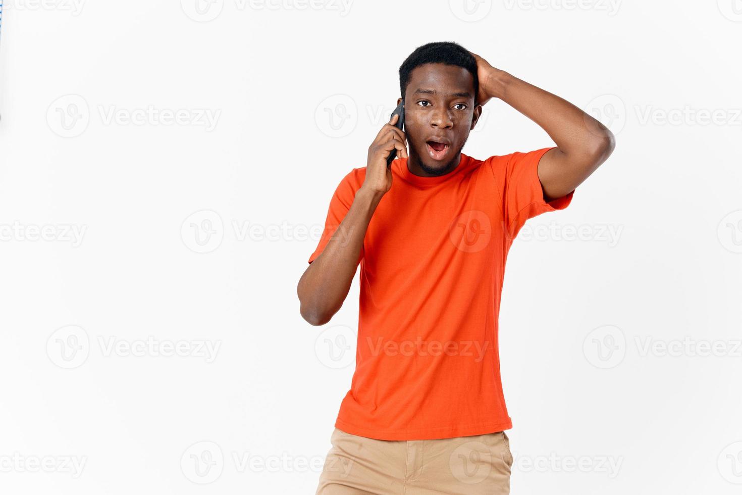 perplexed man of African appearance talking on the phone on a light background 22058441 Stock ...