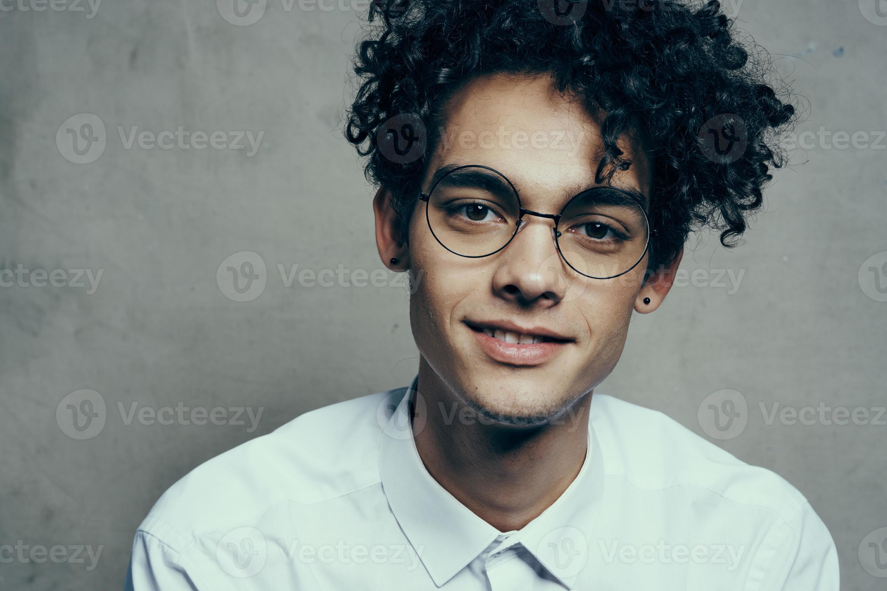 curly-haired man in glasses and in a white shirt on a fabric background ...