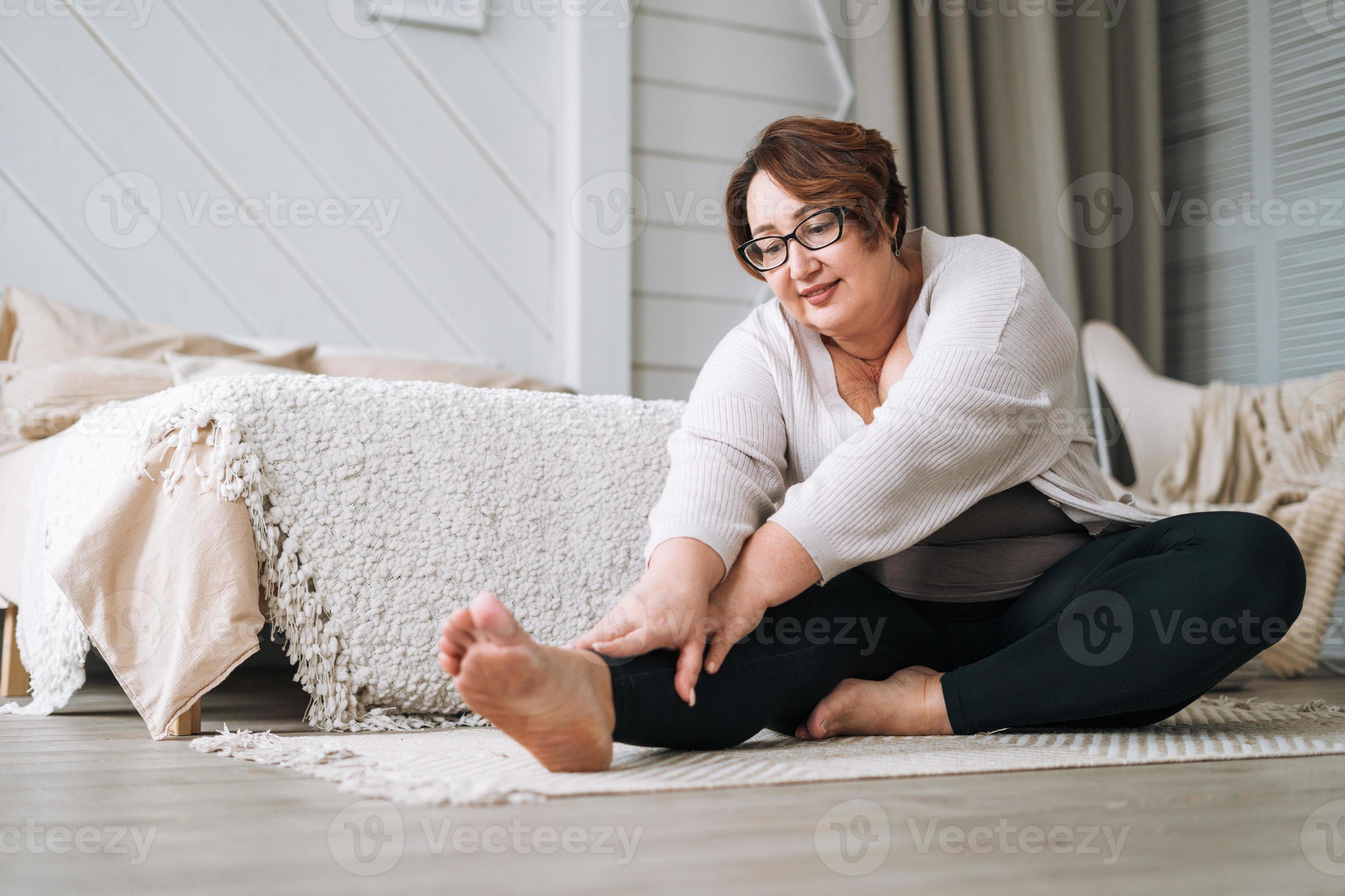 Middle aged plus size smiling brunette woman in home wear doing stretching in bedroom 22145280 ...