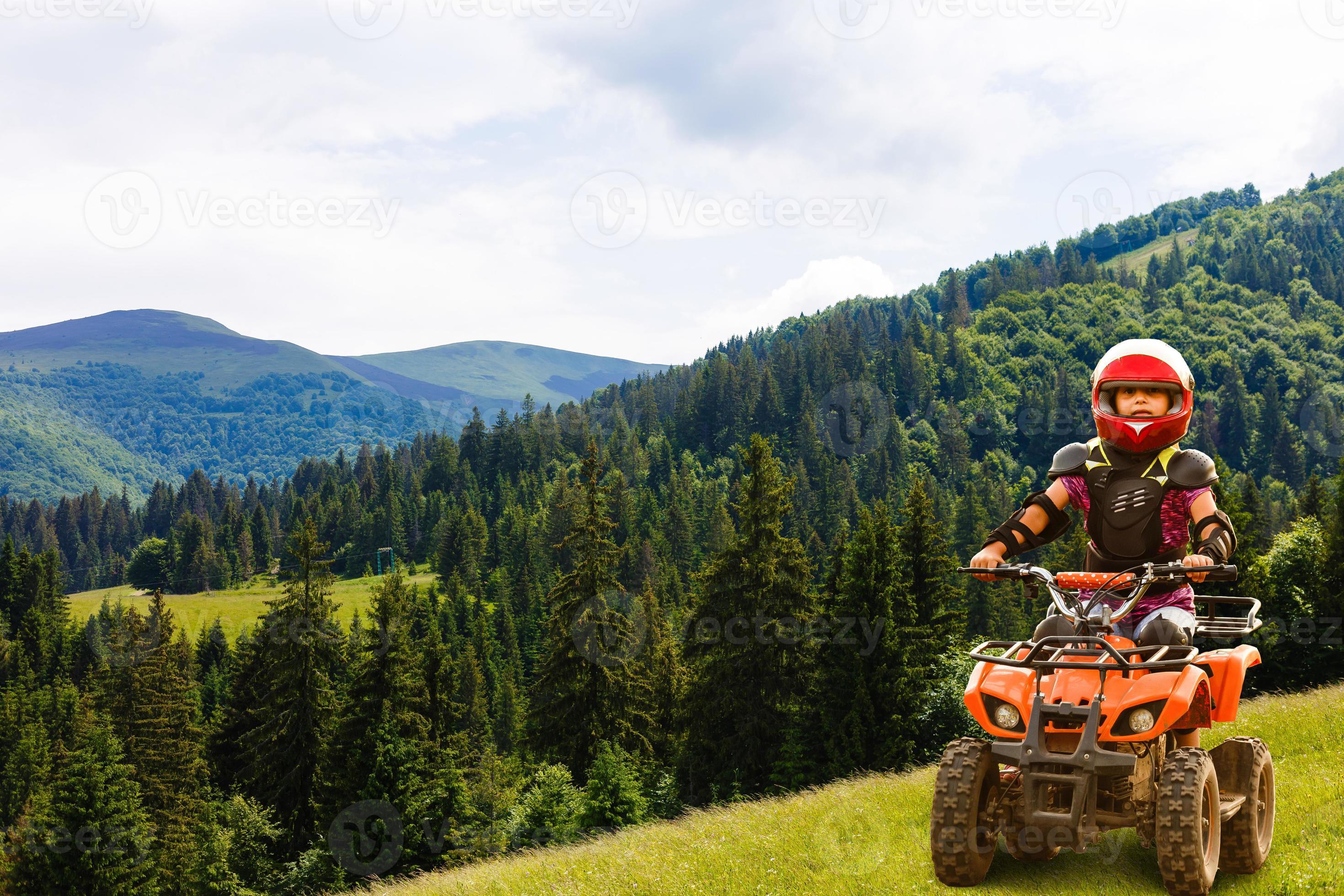 Girl riding quad bike mountain, ATV. Cute child on quadricycle. Kids summer vacation activity ...