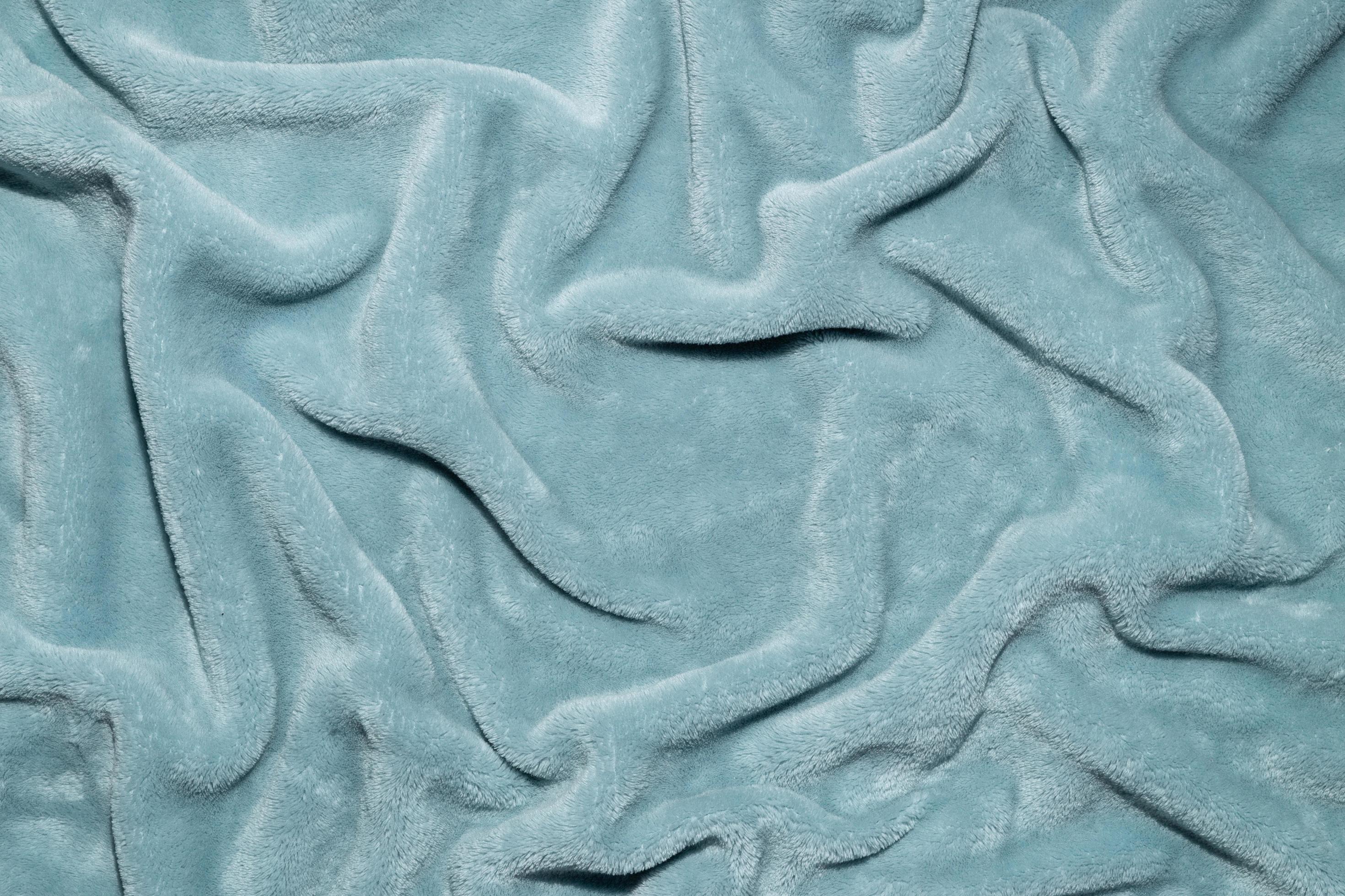 Wavy soft blue fabric texture background, made with Blanket. Top view with Copy space. Minimal ...