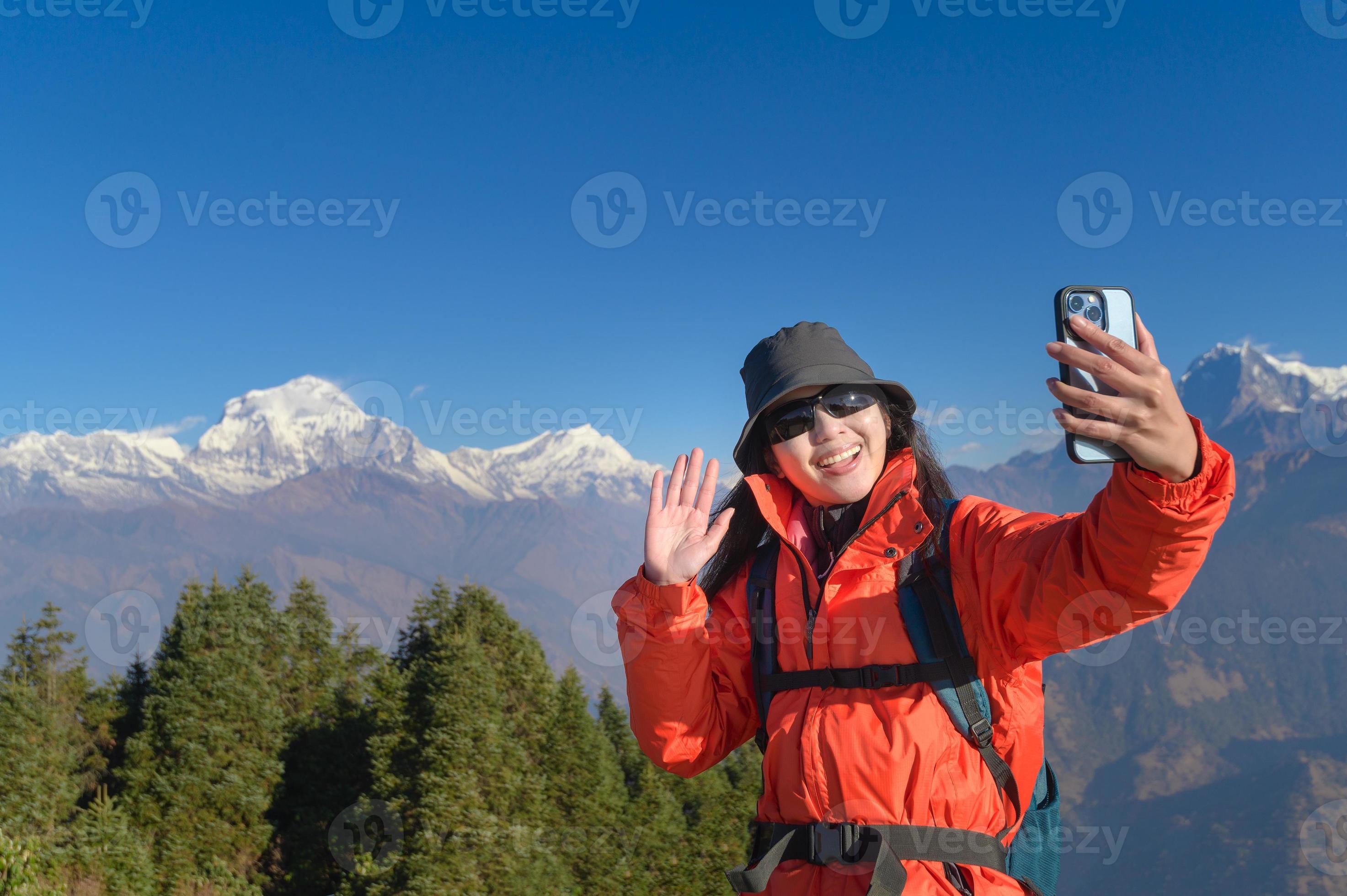 A young traveler takes a selfie or a video call while standing a top a ...