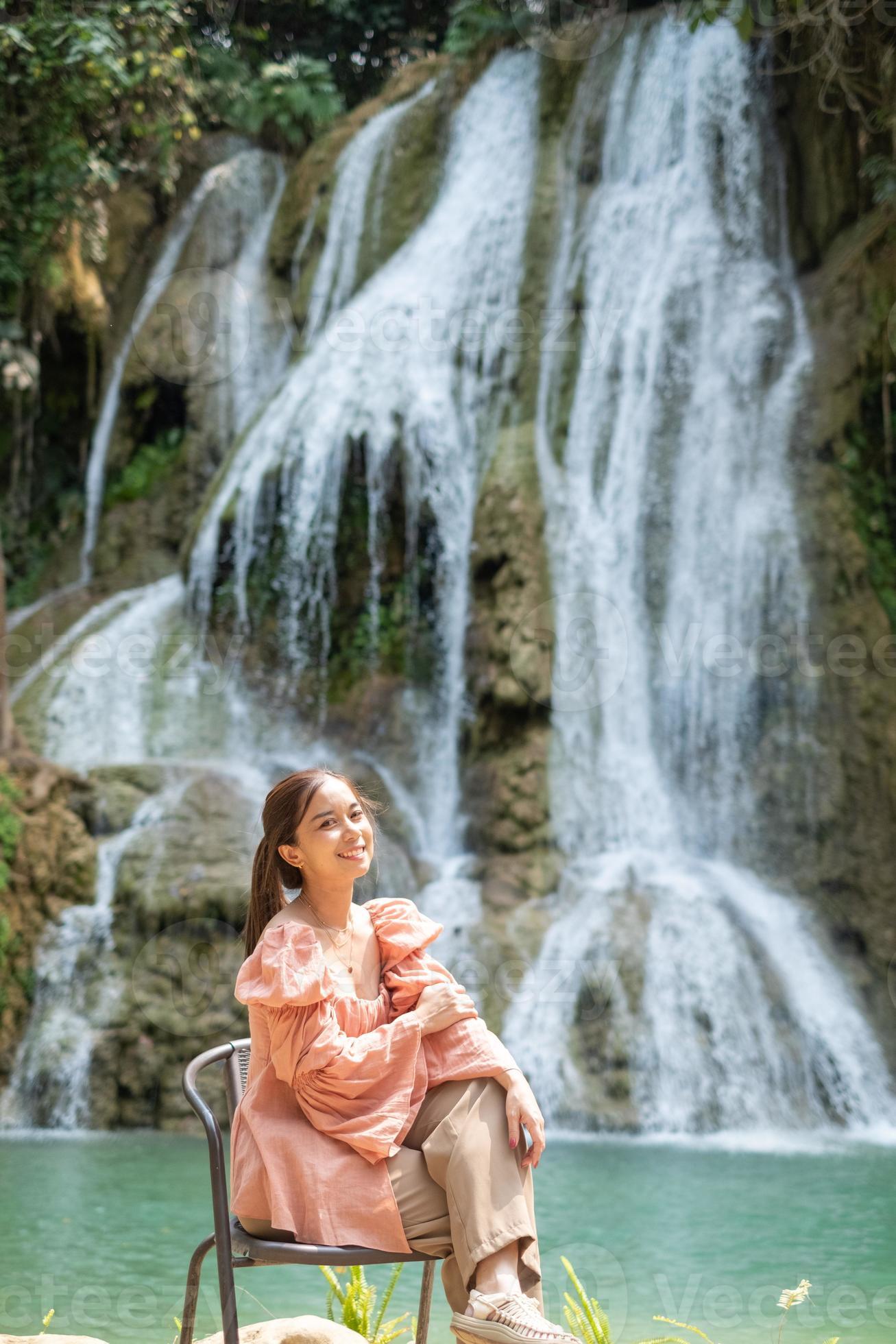 Young Asian woman sitting on a chair In front of the Khoun Moung Keo Waterfall 22574755 Stock ...