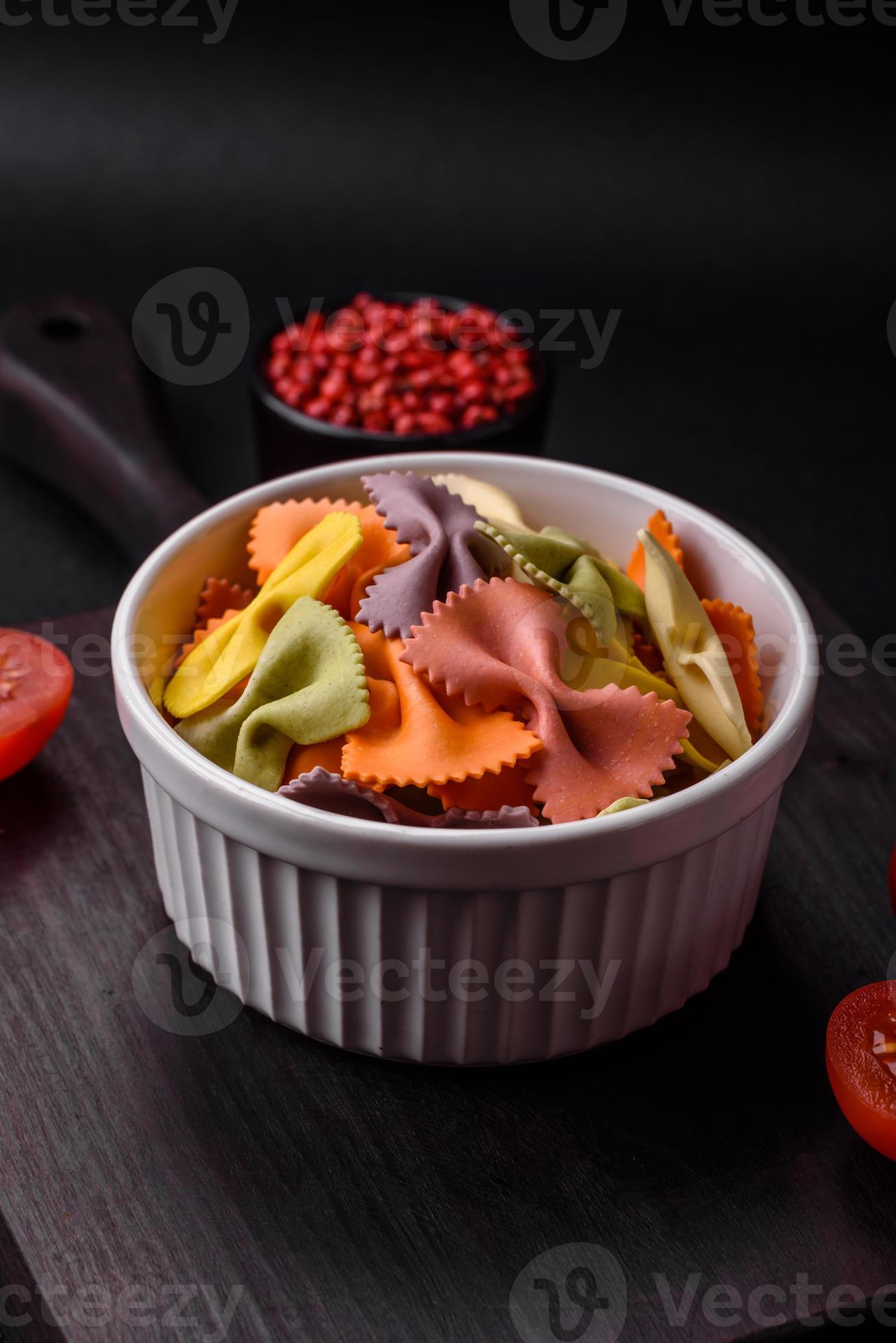 crudo farfalle pasta en diferente colores en un oscuro hormigón ...