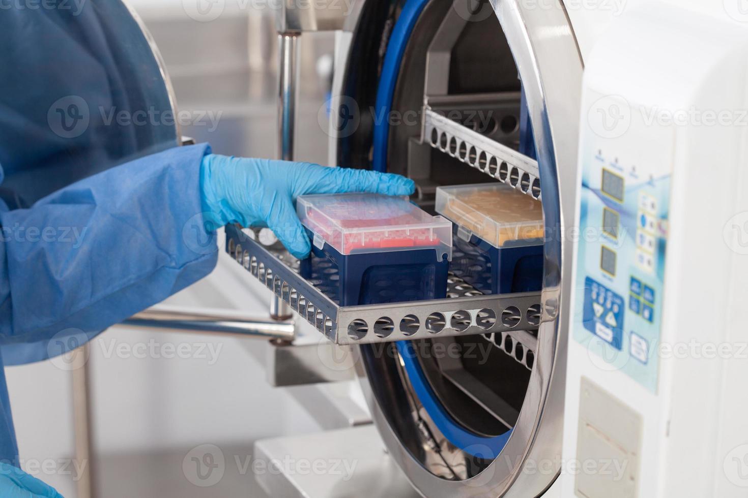 Young female scientist sterilizing laboratory material in autoclave 22750028 Stock Photo at Vecteezy