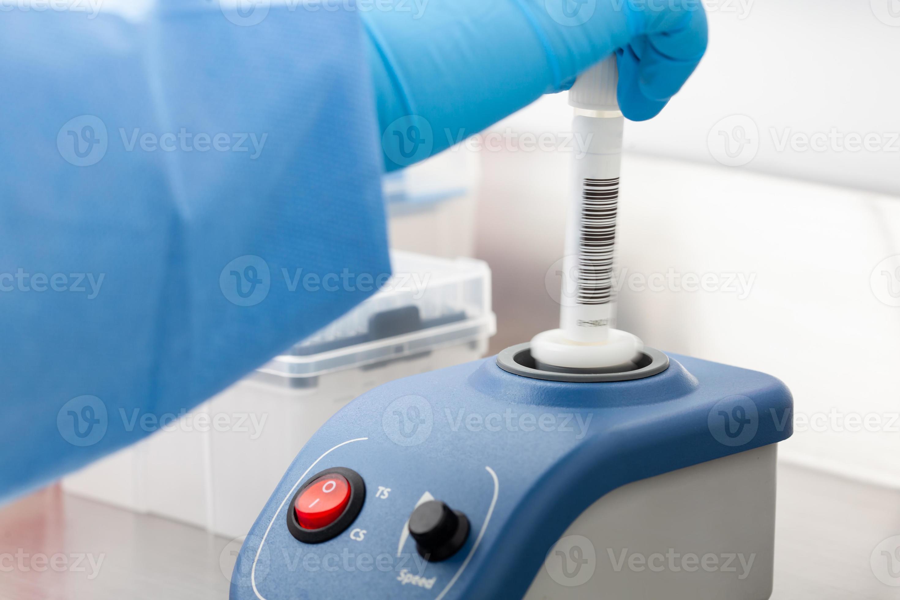 Scientist mixes a biological sample for analysis using a lab vortex ...