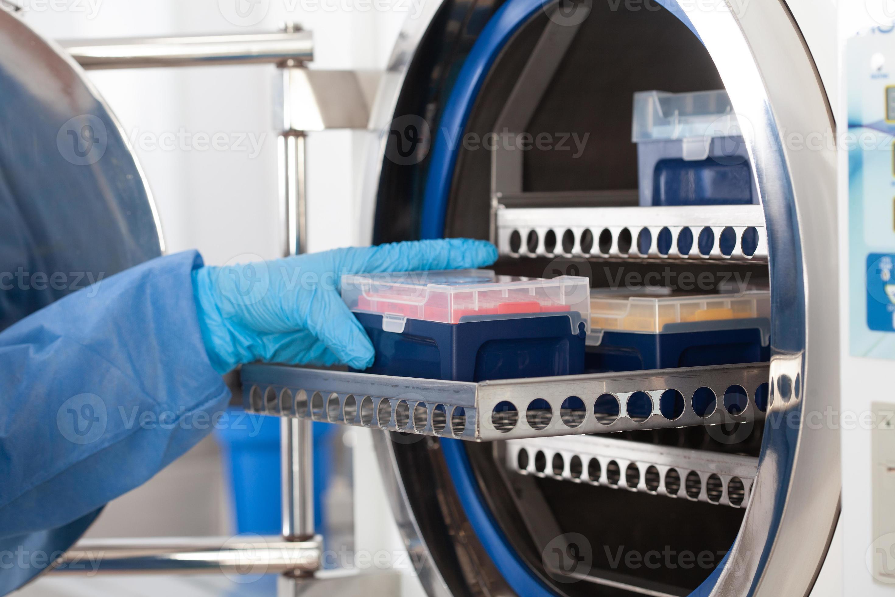 Young female scientist sterilizing laboratory material in autoclave 22750592 Stock Photo at Vecteezy