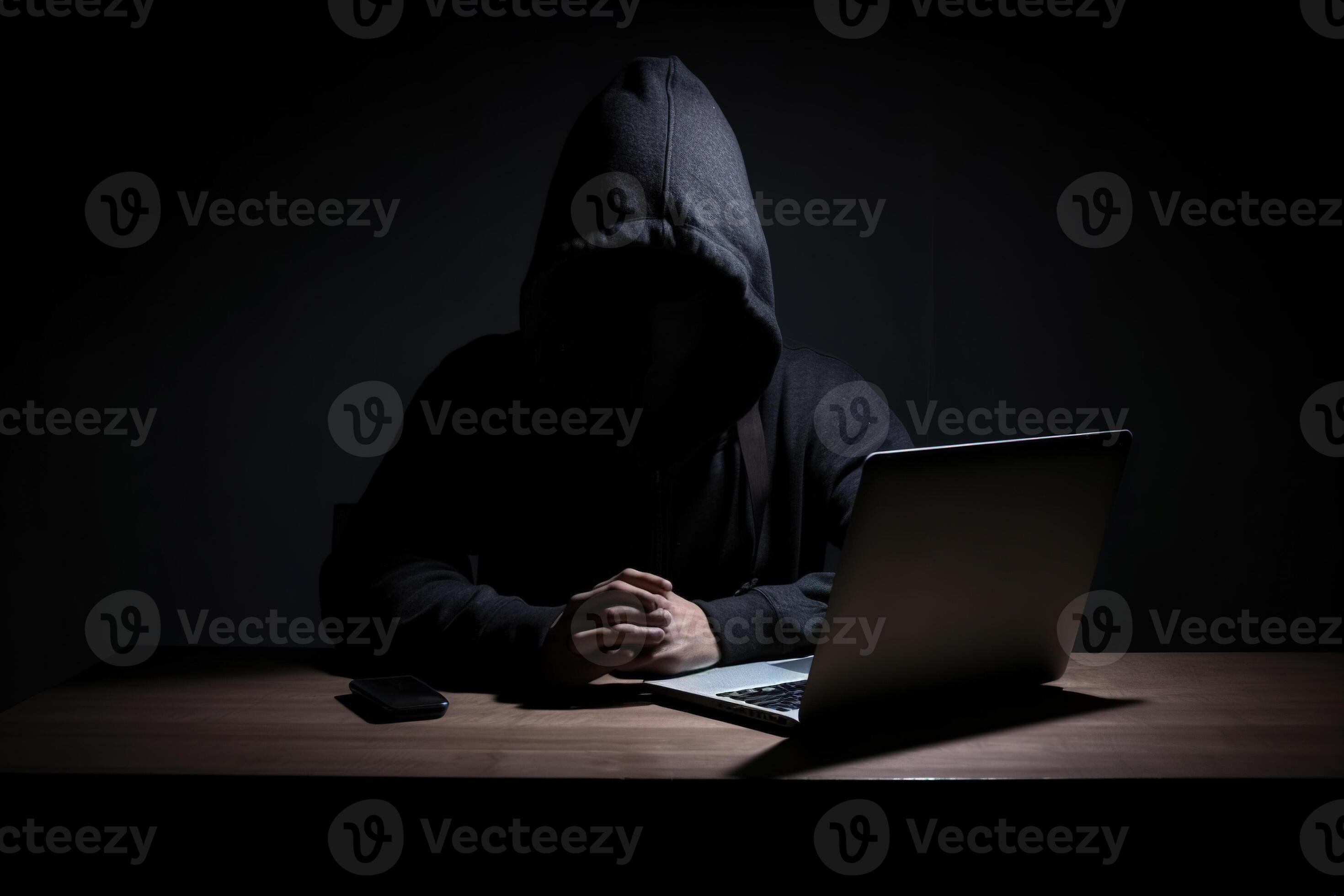 Hacker Wearing Black Hoodie Using Laptop Computer While Working On Dark