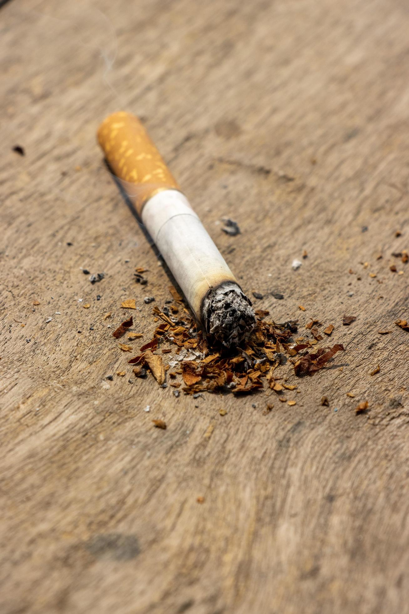 Cigarette Burning On A Wooden Table Cigarette With Tobacco Powder Burning On A Wooden Surface