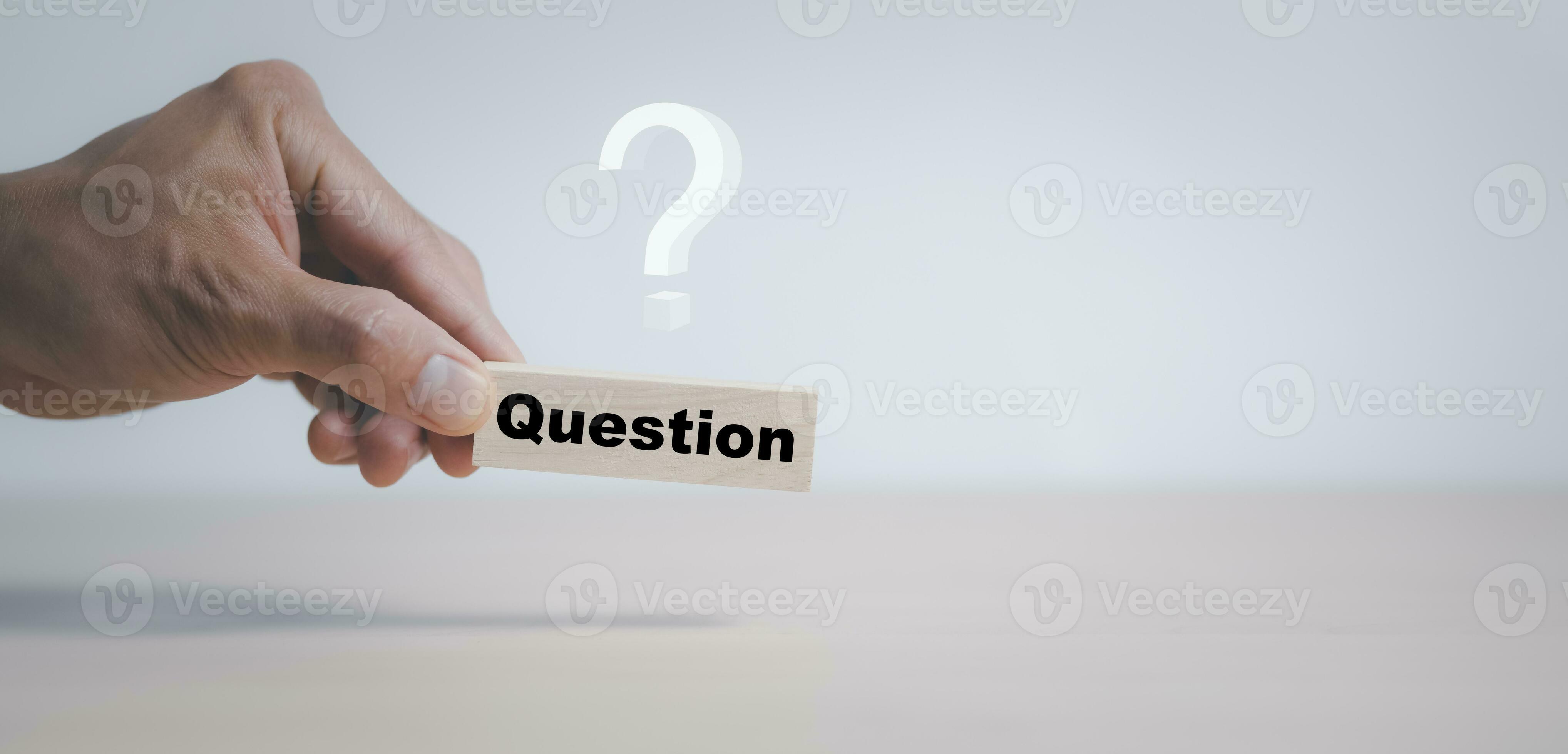 Hand hold Wooden cube block in question mark mean what on cement table ...