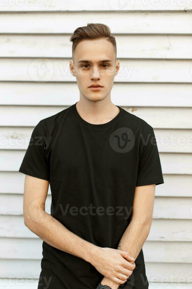 Handsome man in black t-shirt near the white wooden wall. 23334452 ...