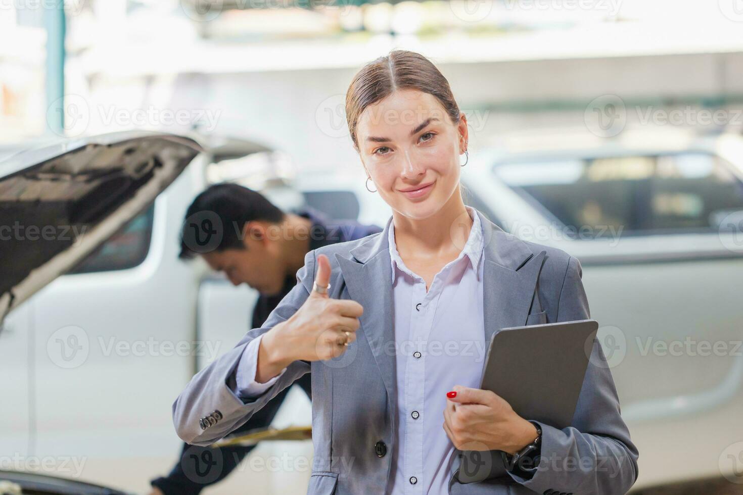 Female manager and car mechanic while working in auto repair shop, Young business woman with ...