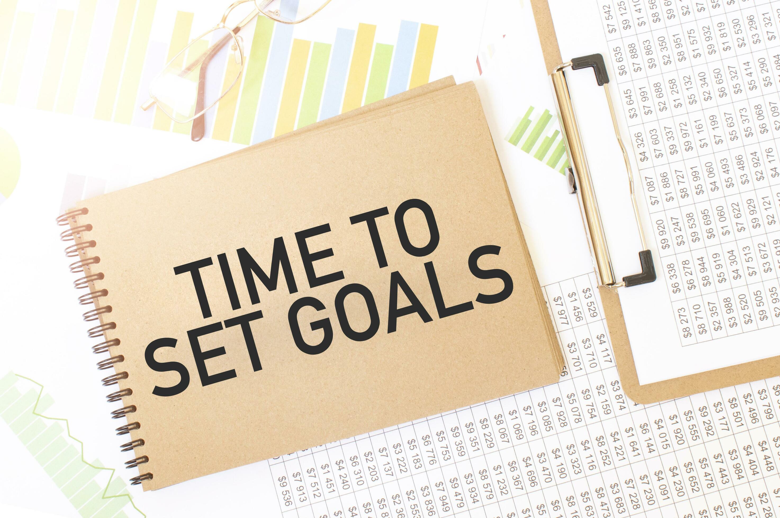 Business up graph on a sheet of craft colour Notepad with TIME TO SET GOALS sign. Notepad on ...