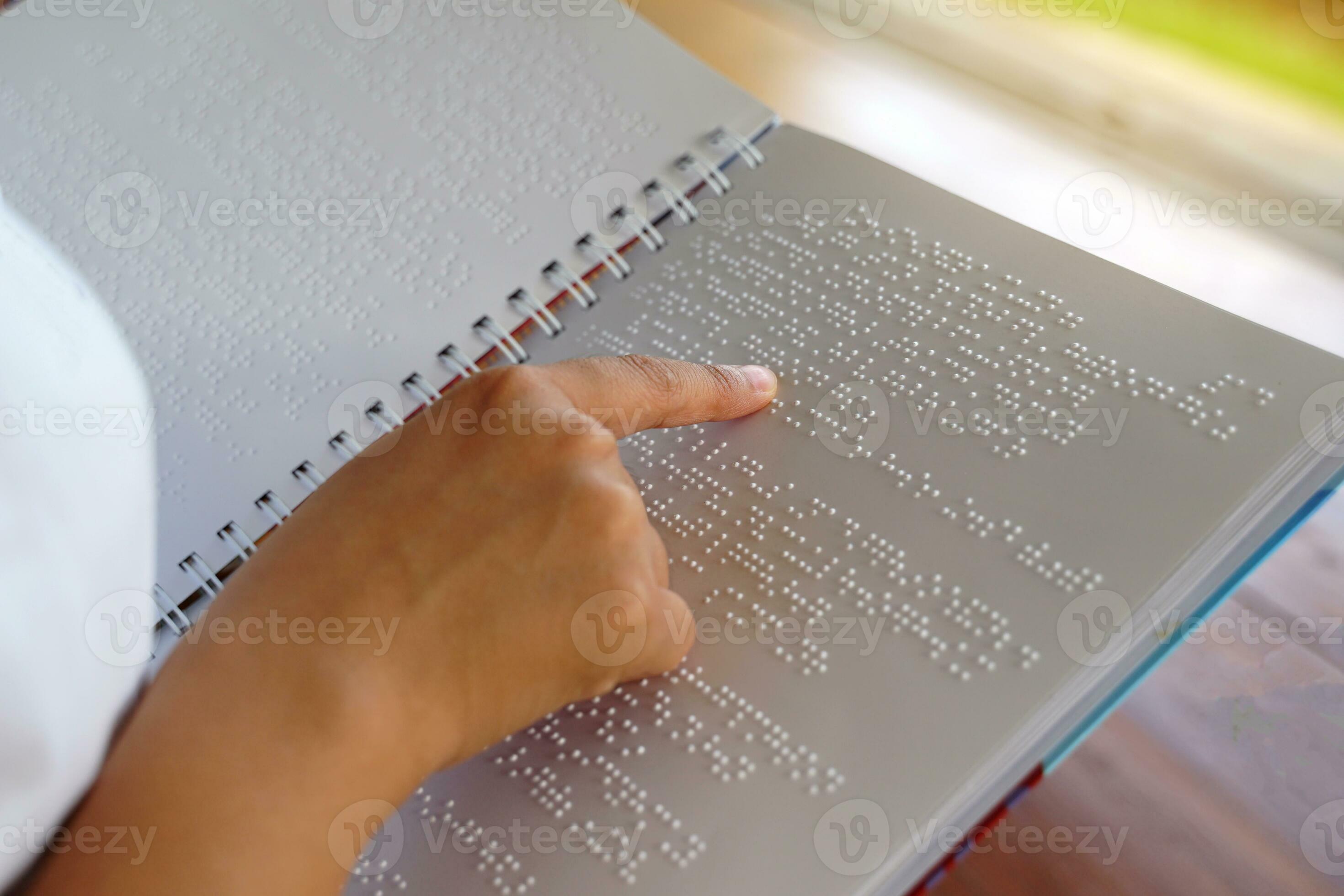 Visually impaired person reads with his fingers a book written in braille It is written for ...