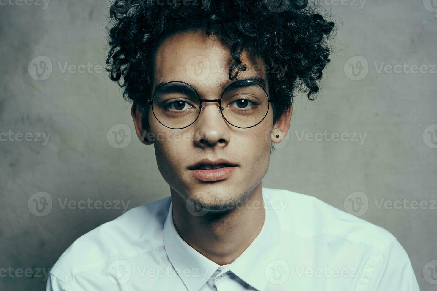 curly-haired man in glasses and in a white shirt on a fabric background ...
